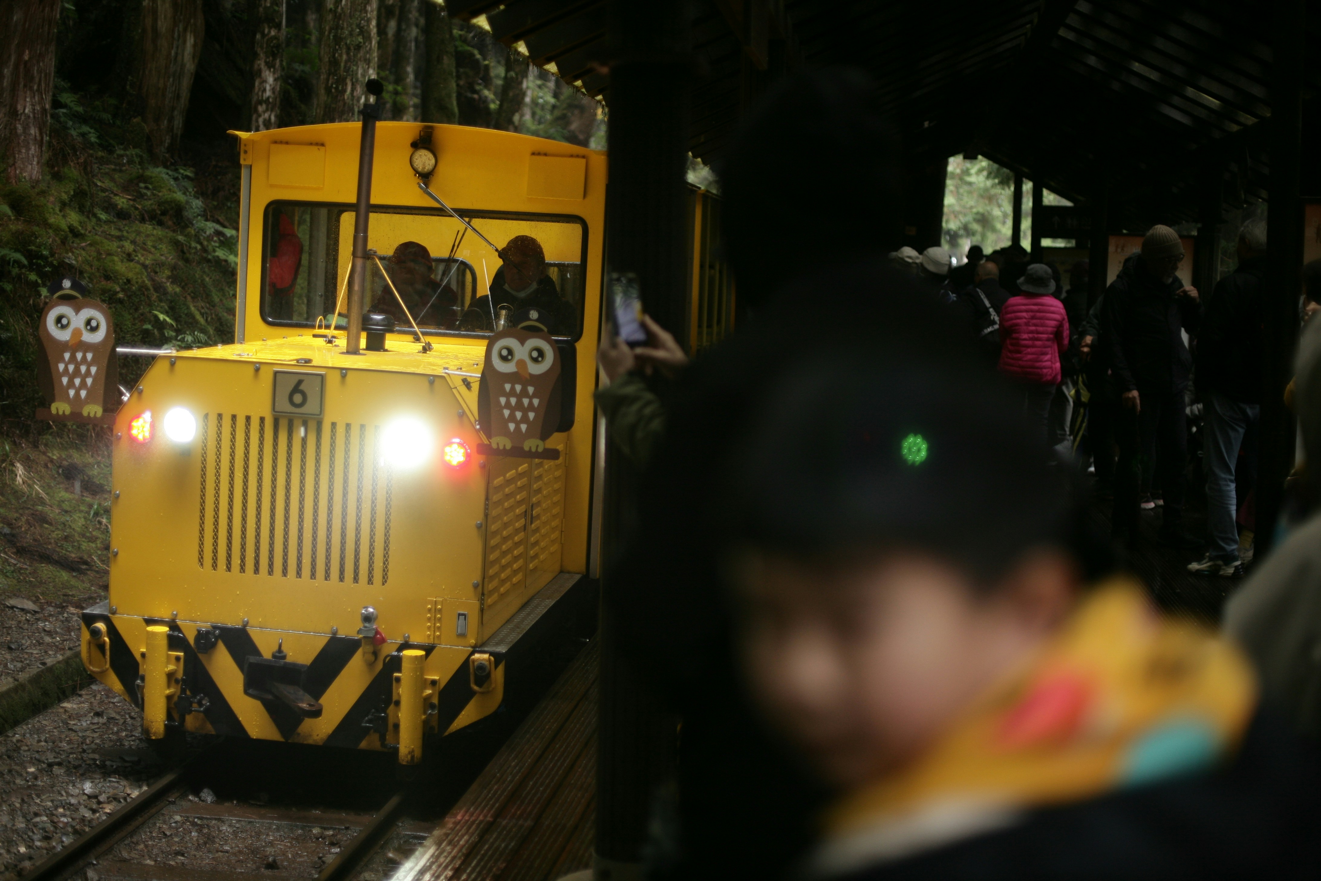 Front-Facing Yellow Diesel Locomotive at a Dim Platform, Surrounded by Onlookers