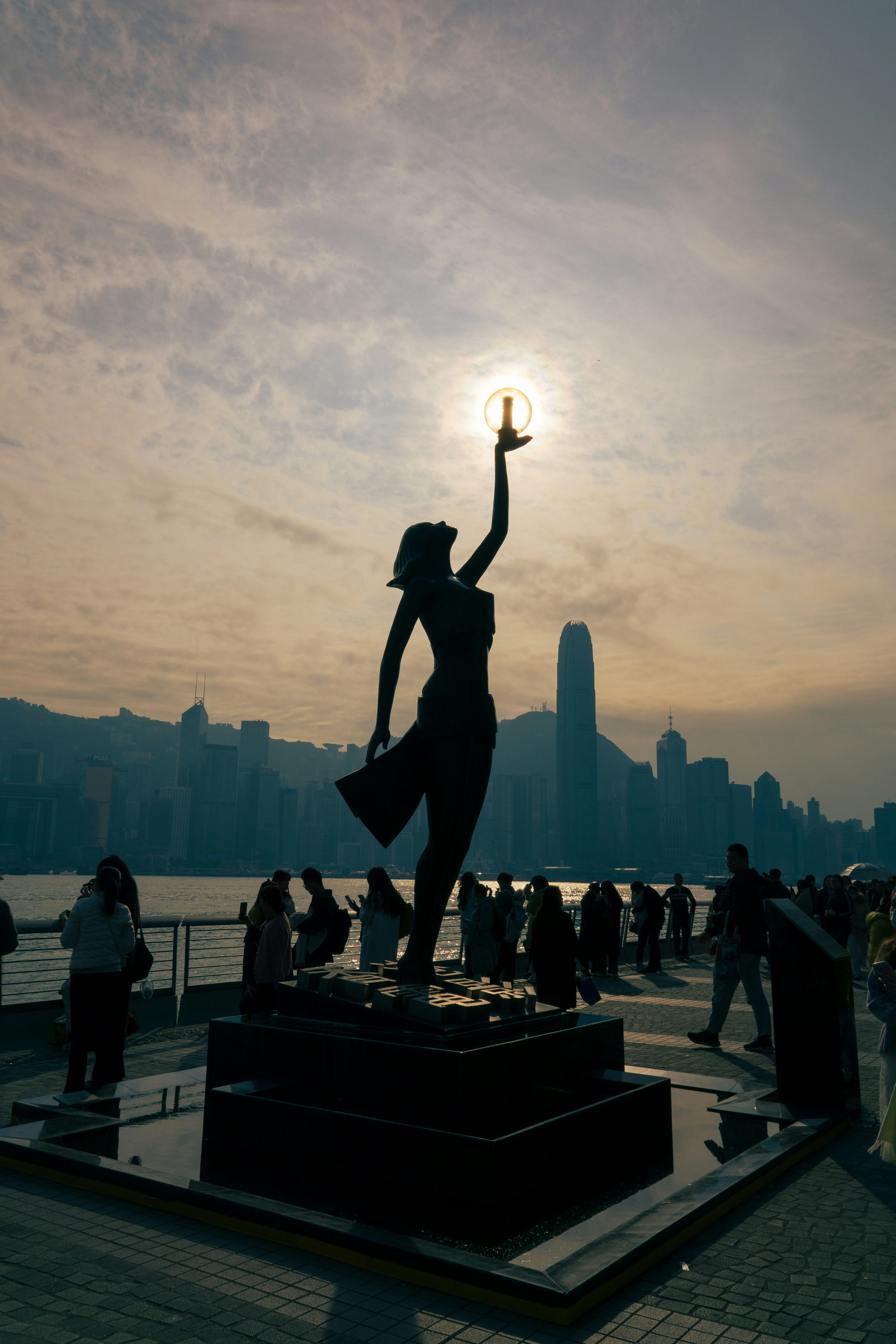 Silhouette of a woman holding a glowing orb against a backdrop of a bustling city skyline at dusk. The scene captures the essence of hope and determination.