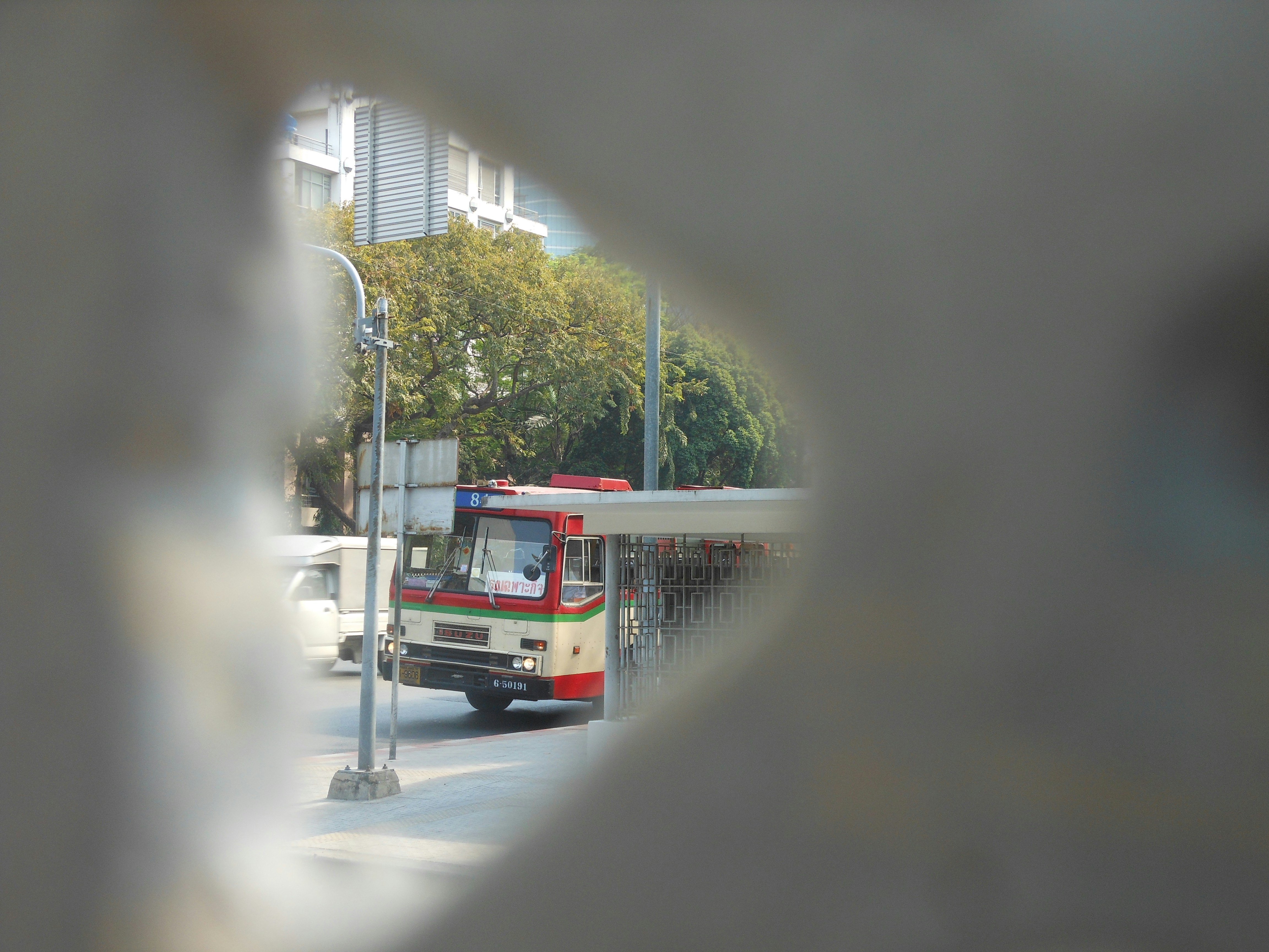A bus is seen through a hole in a wall photo – Free Bus stop Image on ...