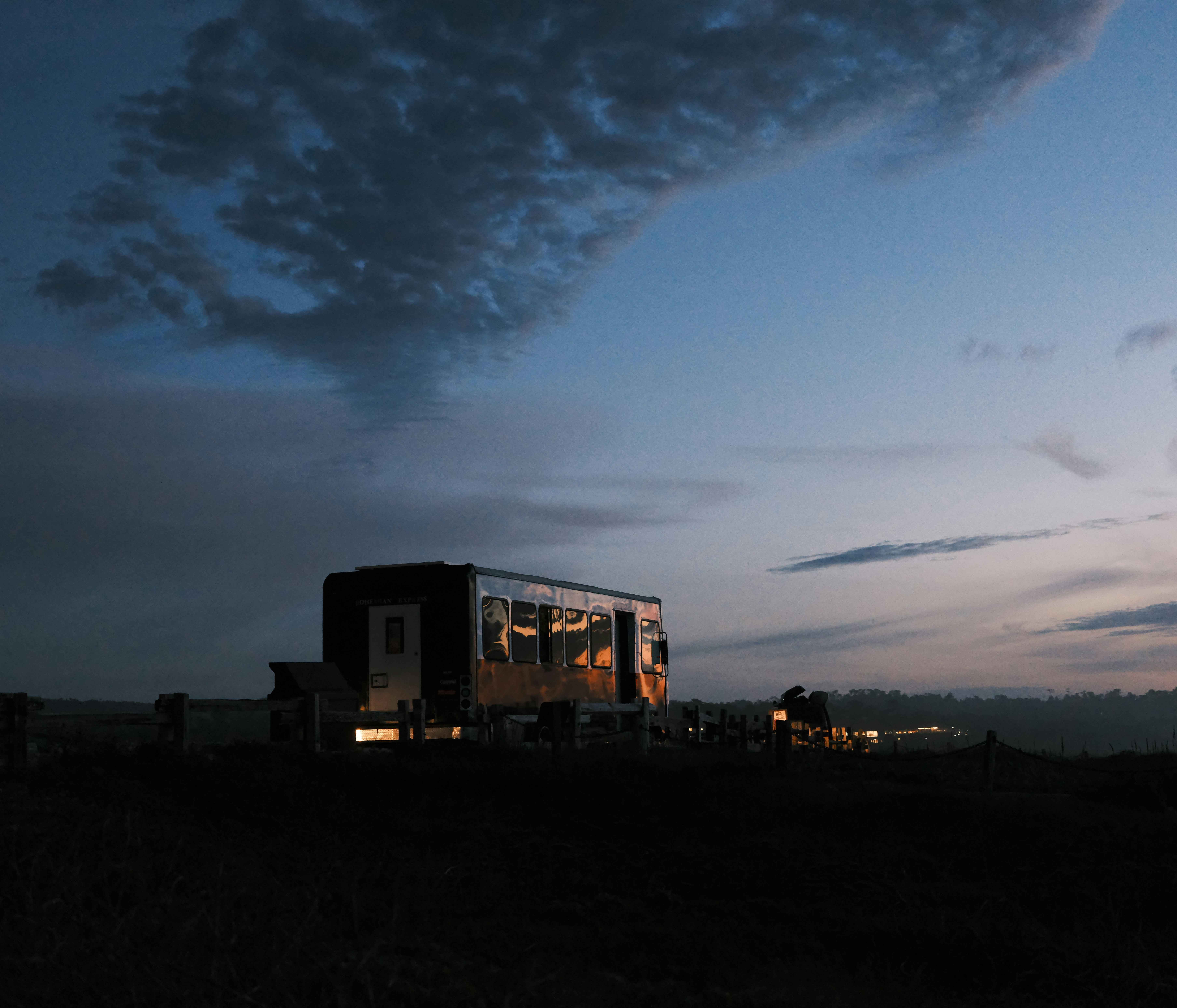Dusk Stopover: A Lone Touring Bus Illuminated in a Quiet Prairie