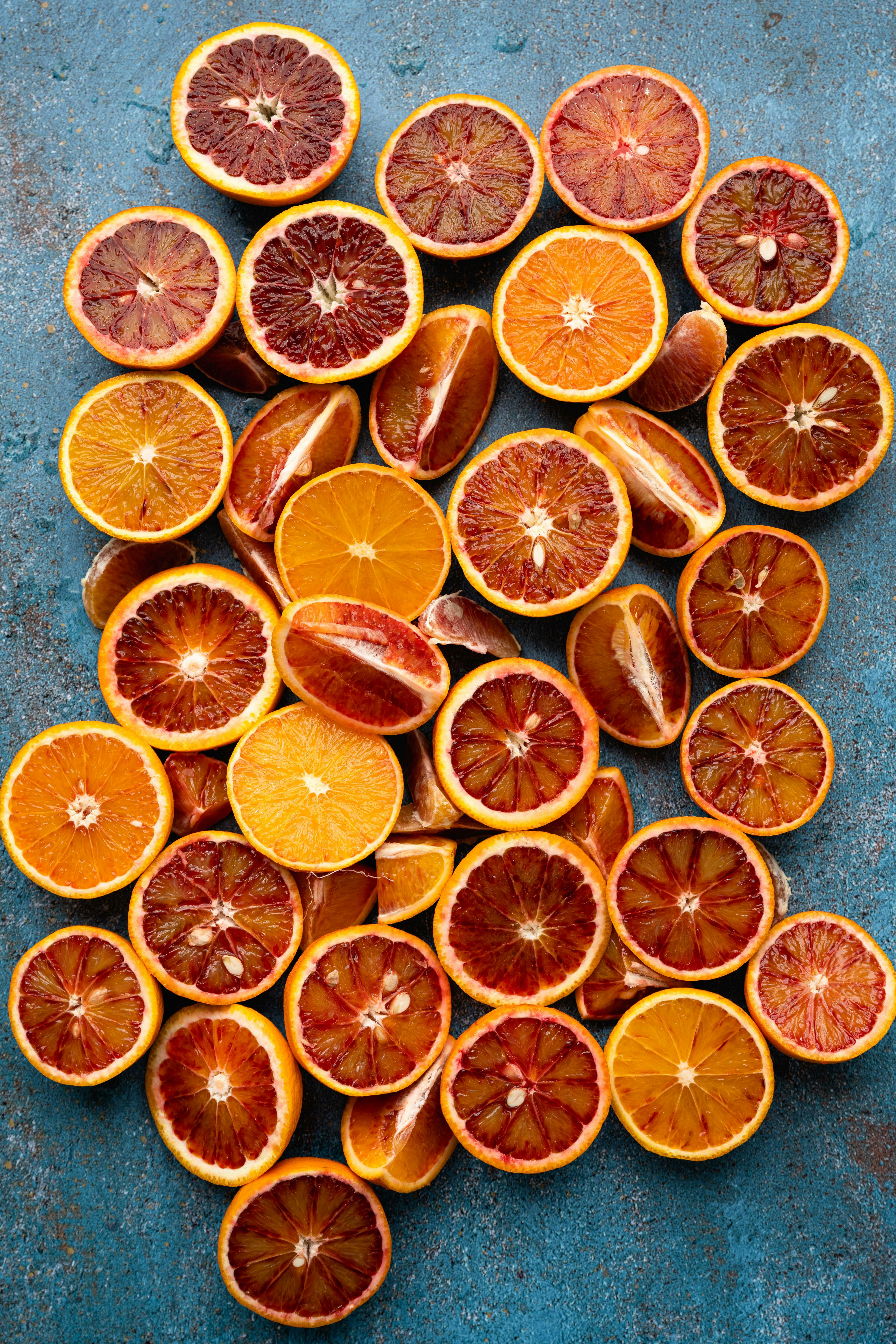 A pile of oranges cut in half on a blue surface photo – Free Produce ...