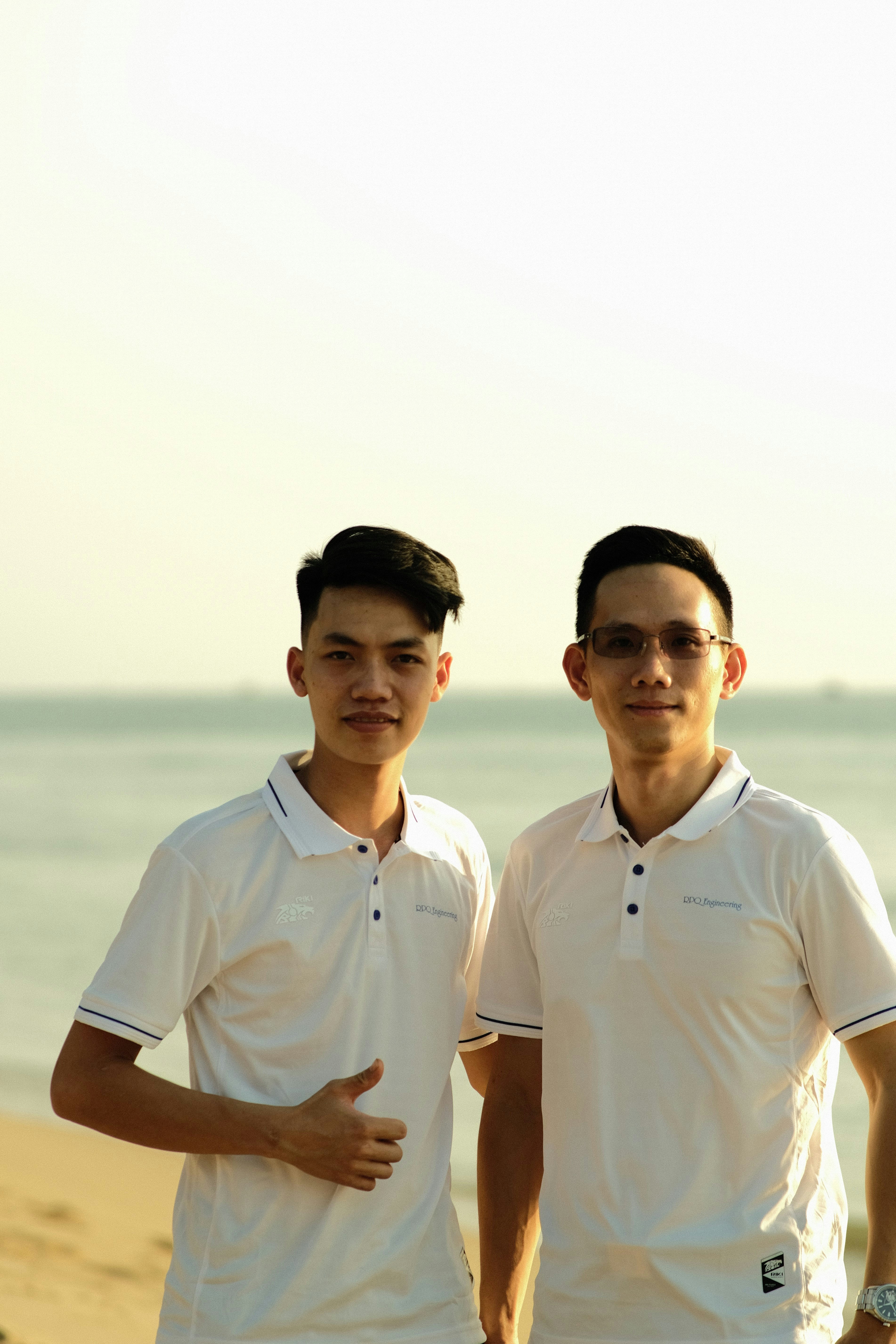 Two men standing next to each other on a beach photo – Free Beach Image ...