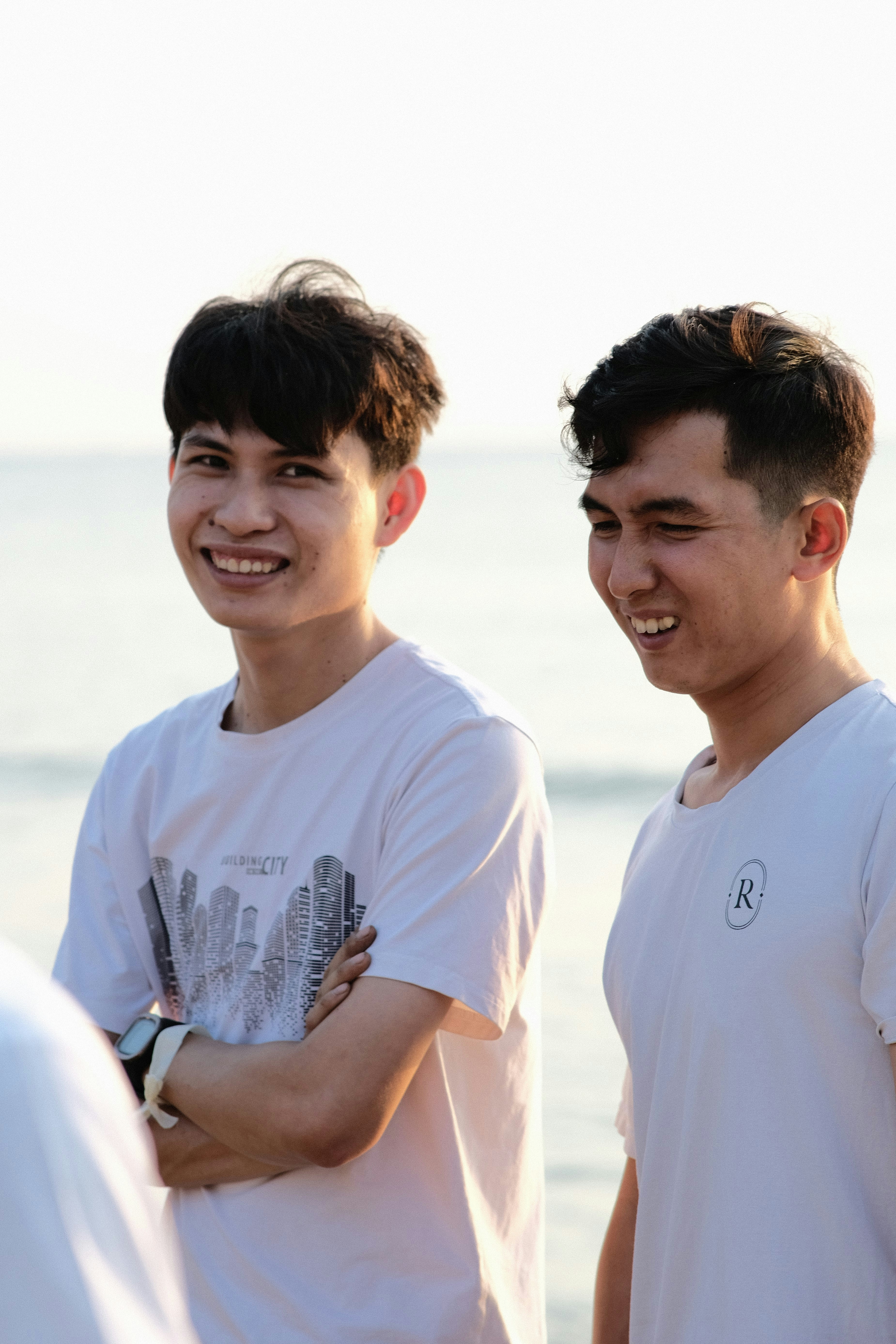 Two young men standing next to each other near the ocean photo – Free ...