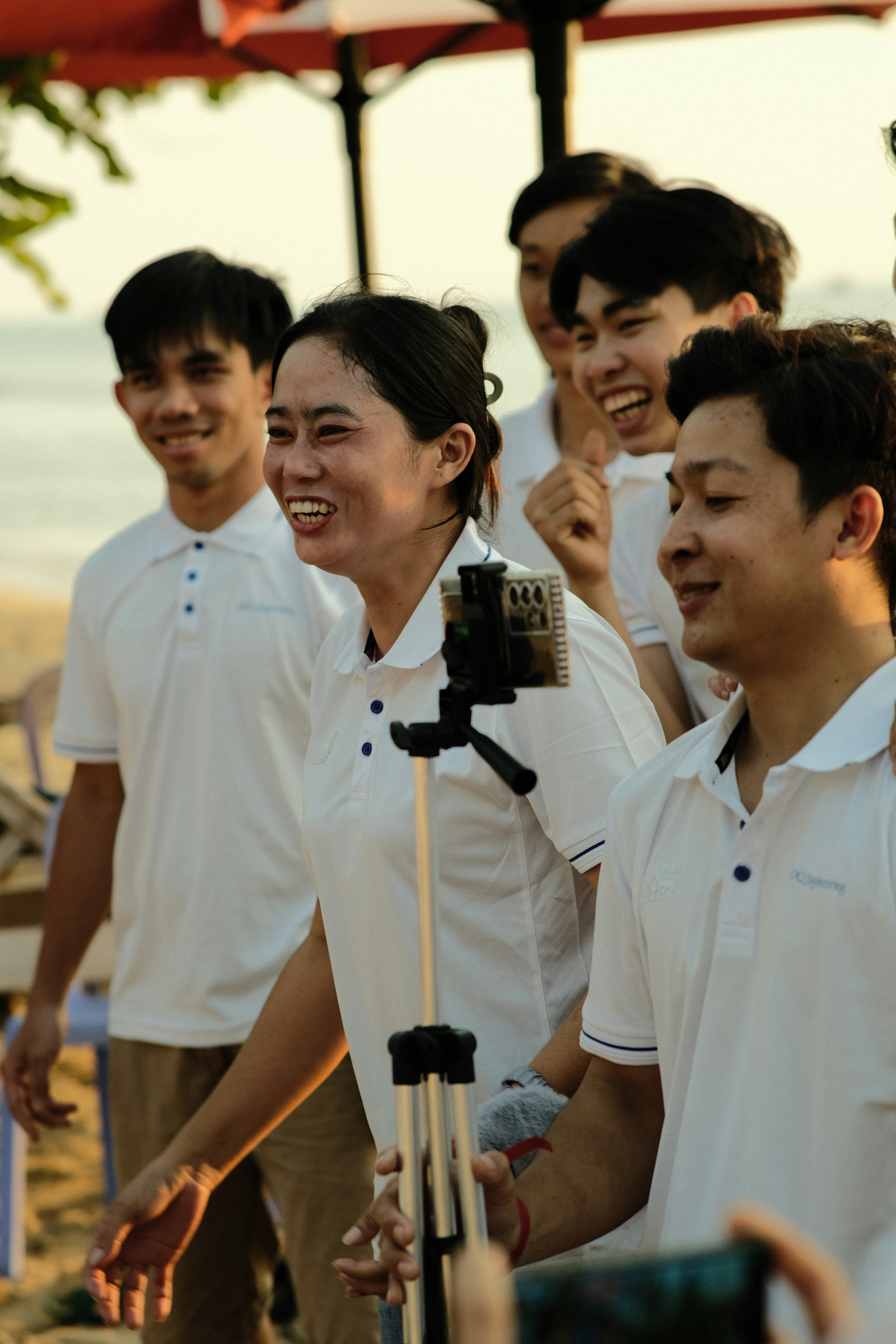 Group selfie on the beach: smiling teammates with a mounted camera rig