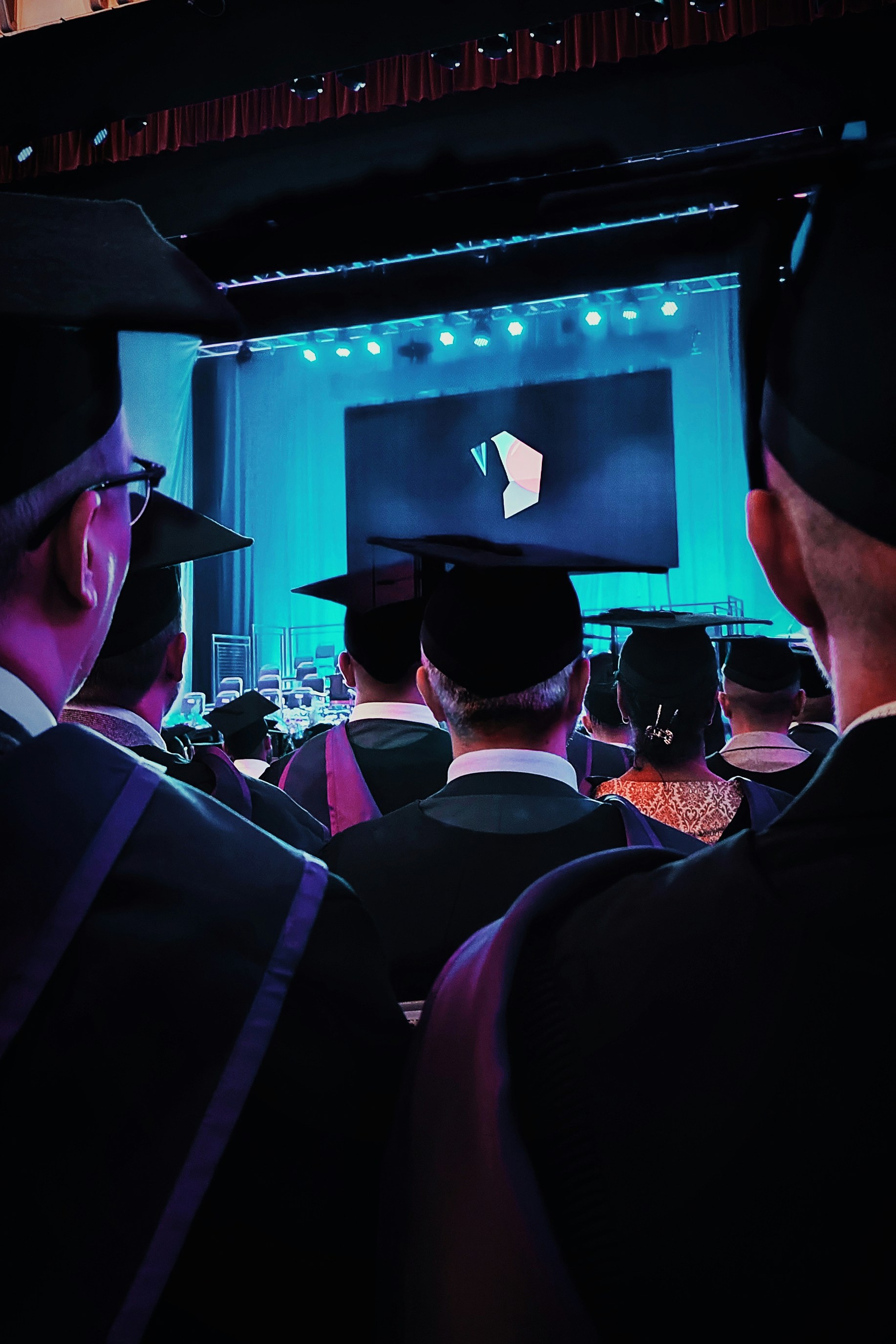 Un groupe de personnes en robes de graduation regardant un écran photo ...