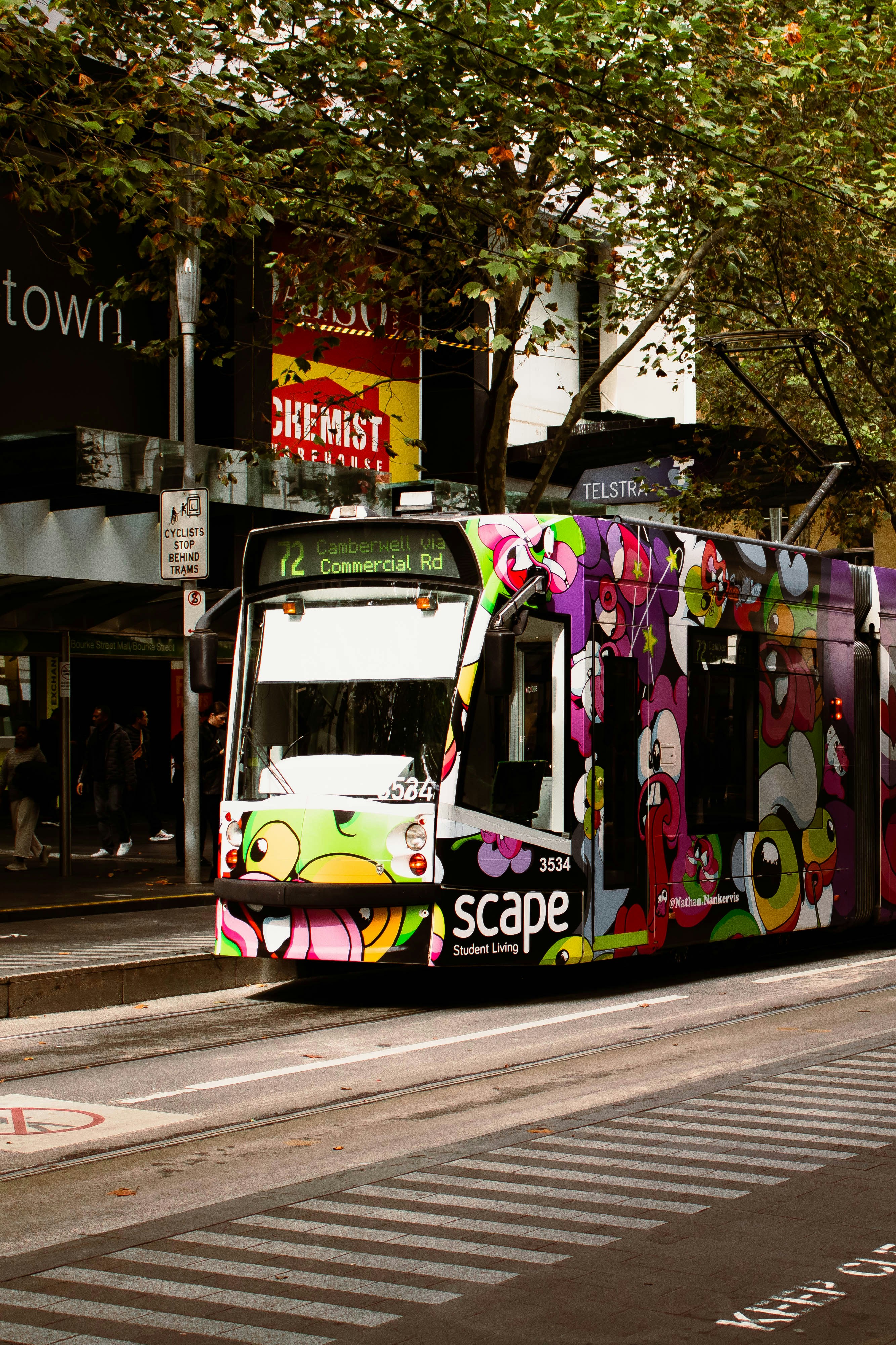 Cartoon-Wrapped Tram Traverses a Shaded City Street