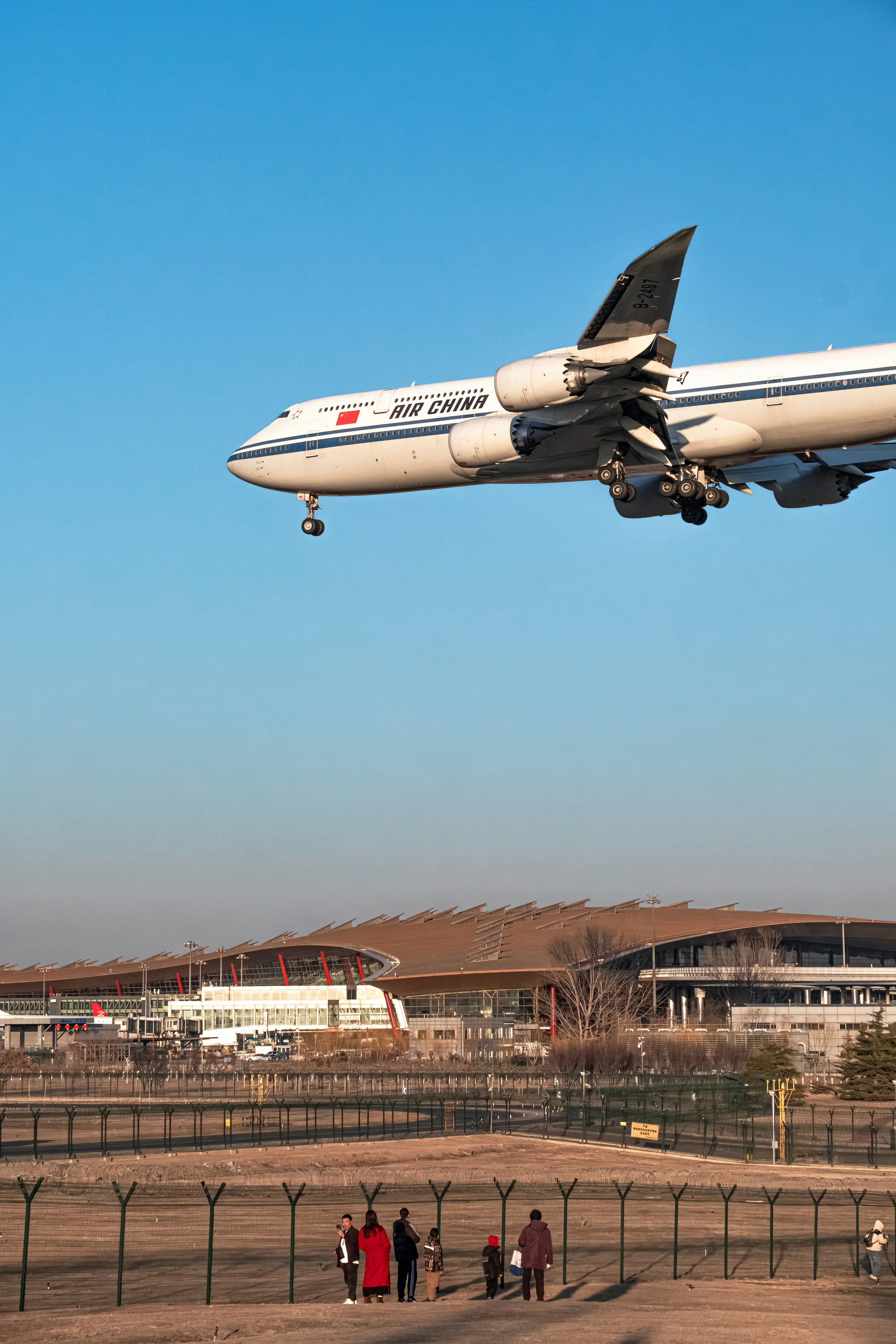 Winged Mission Over a Fence-Line: Air China Jet Glides Toward a Modern Terminal