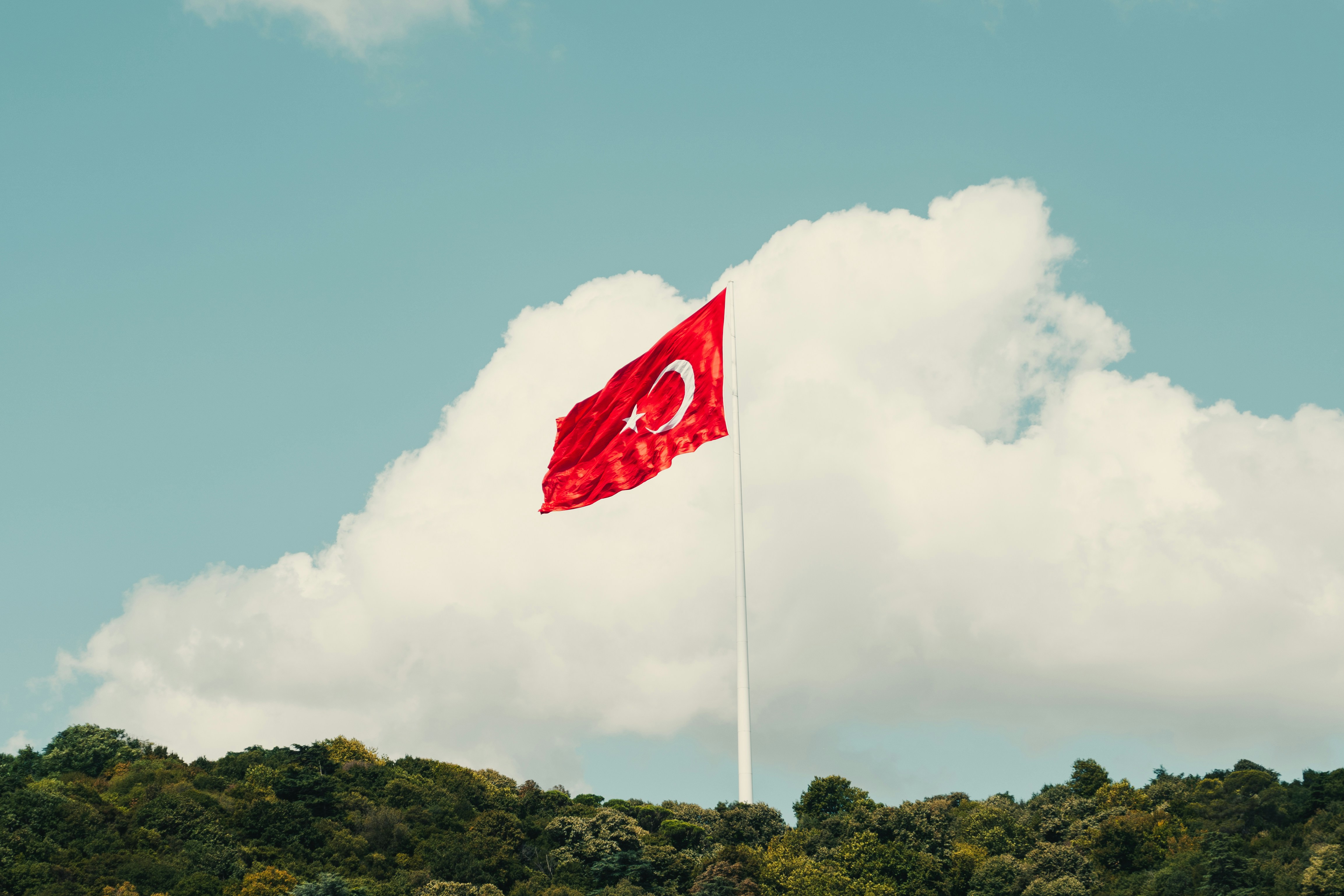 A red flag flying in the wind on top of a hill photo – Free Istanbul ...
