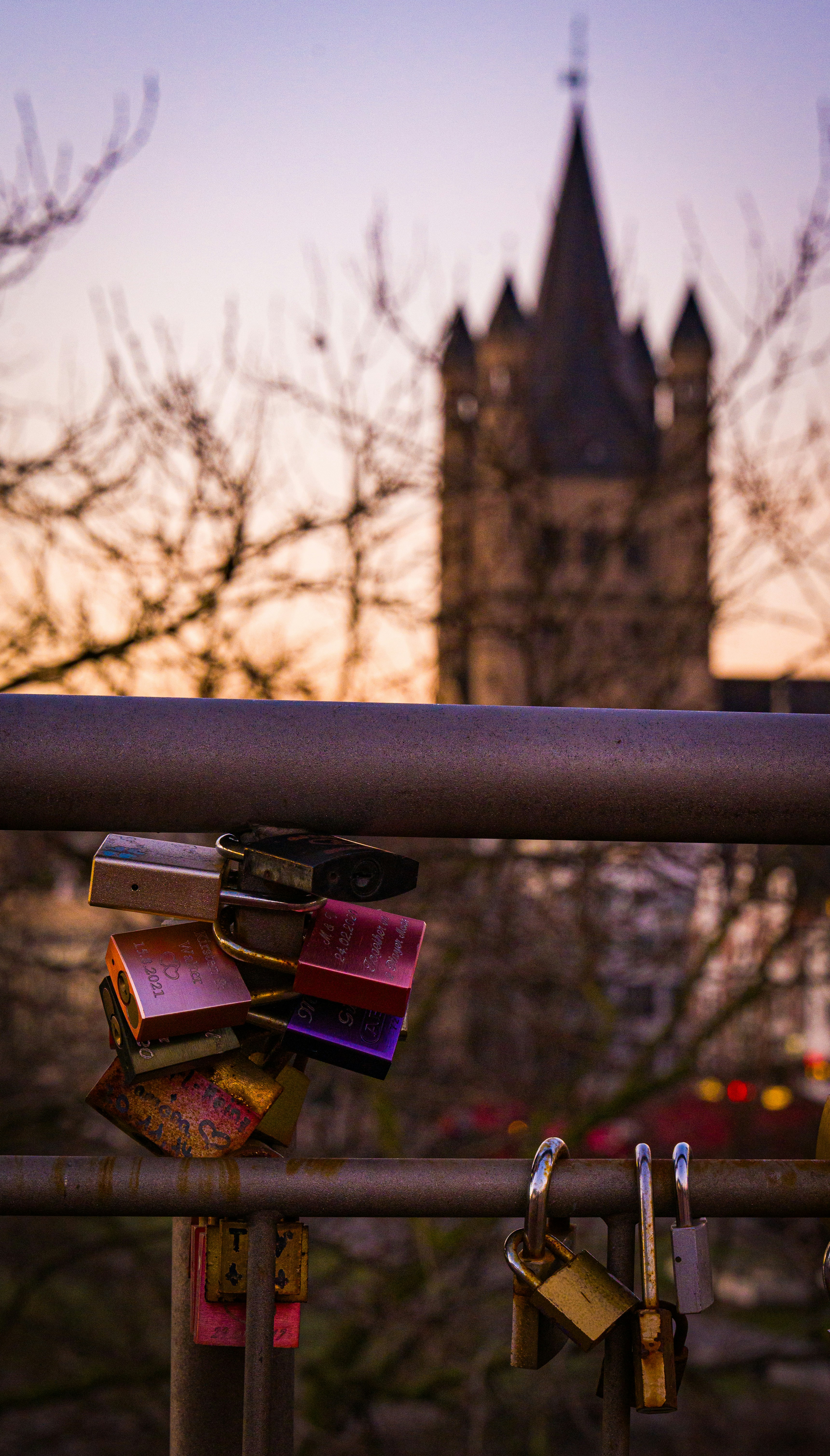 Dusk on the Rails: Love Locks Framing a Blurred Gothic Spire