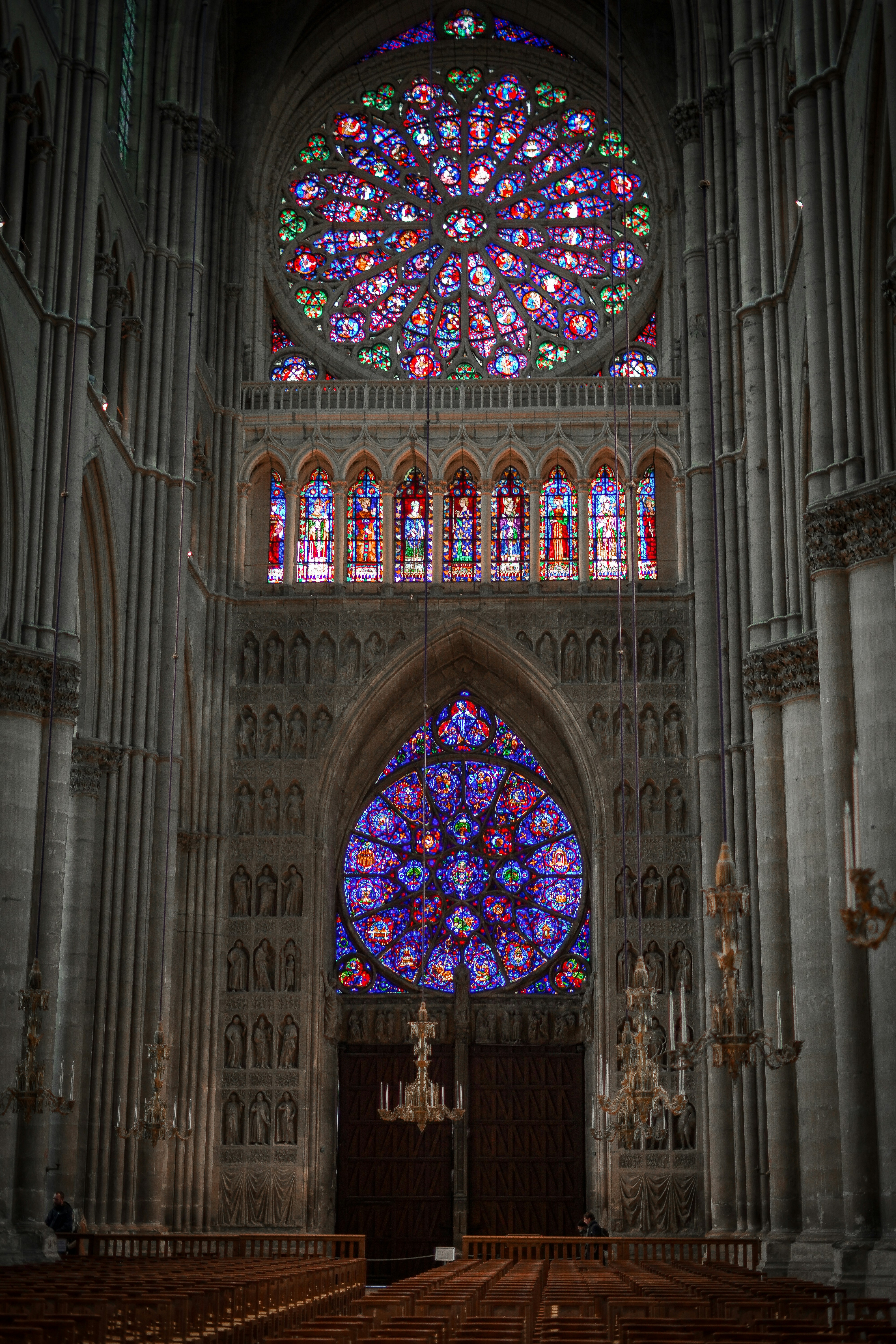 Intricate stained glass rose window and arches inside a grand cathedral.