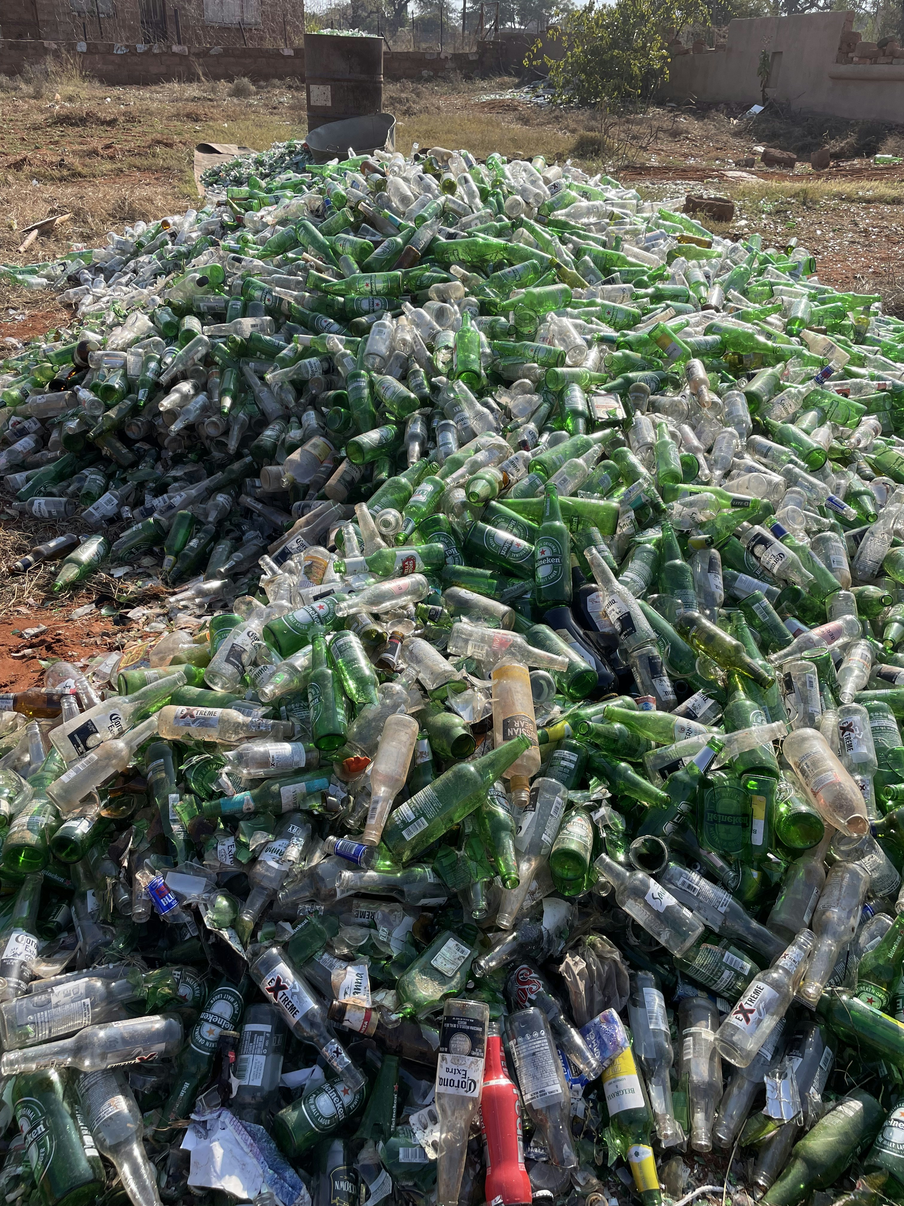 A pile of empty beer bottles sitting on top of a field photo – Free ...
