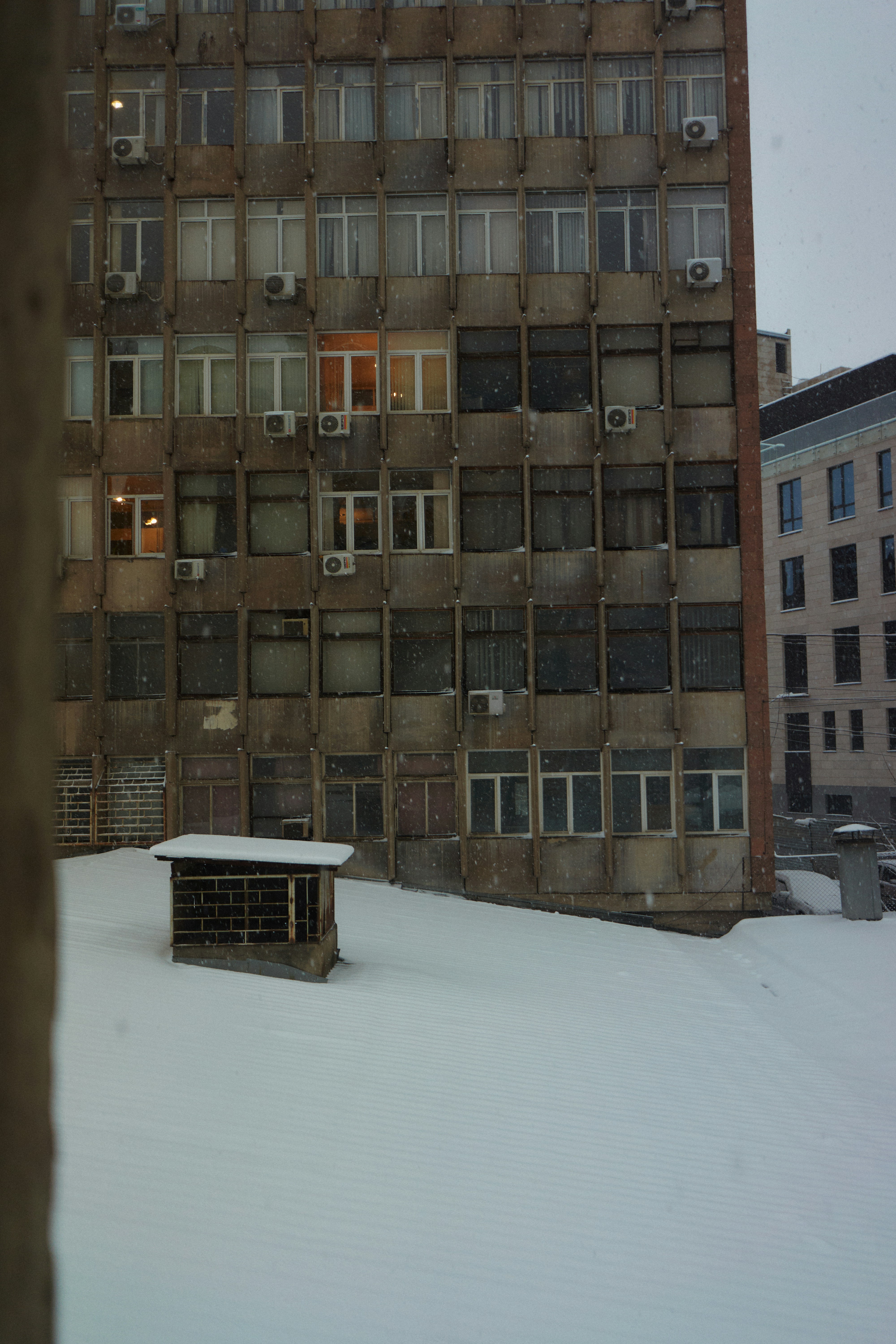 One Warm Window Amid a Snow-Dusted Facade Grid