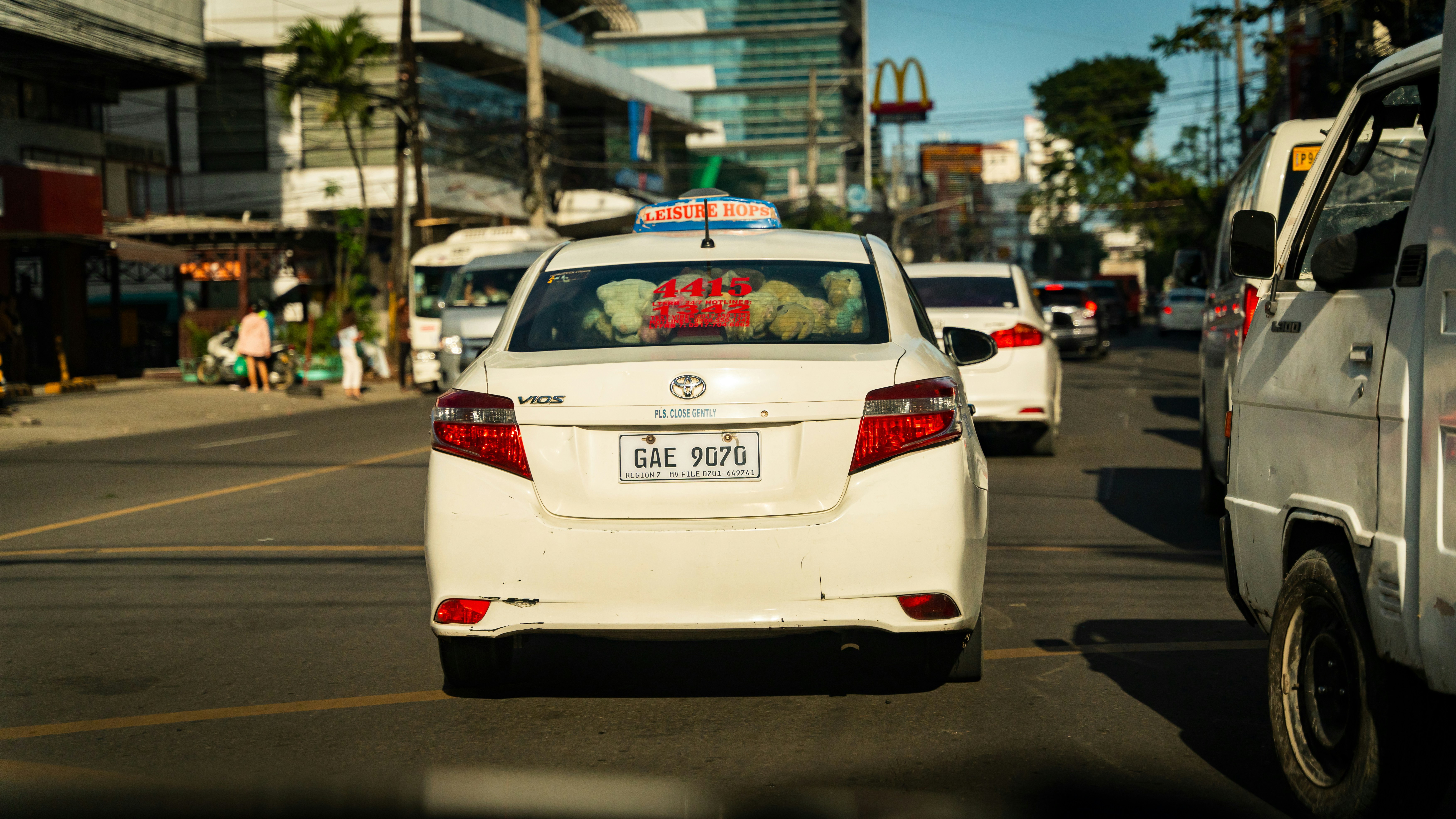 A white taxi cab driving down a street next to tall buildings photo ...