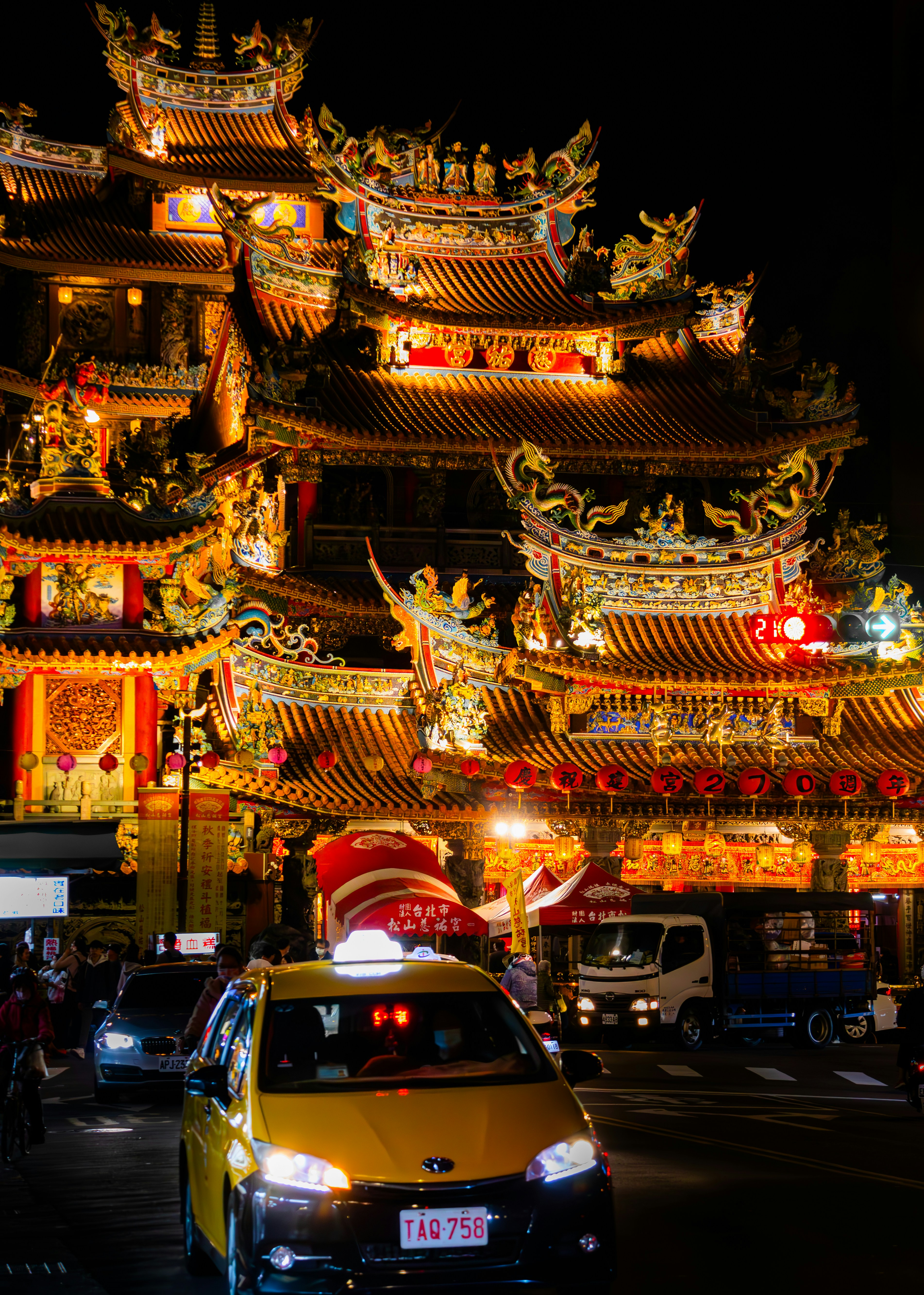 A yellow car driving down a street next to tall buildings photo – Free ...