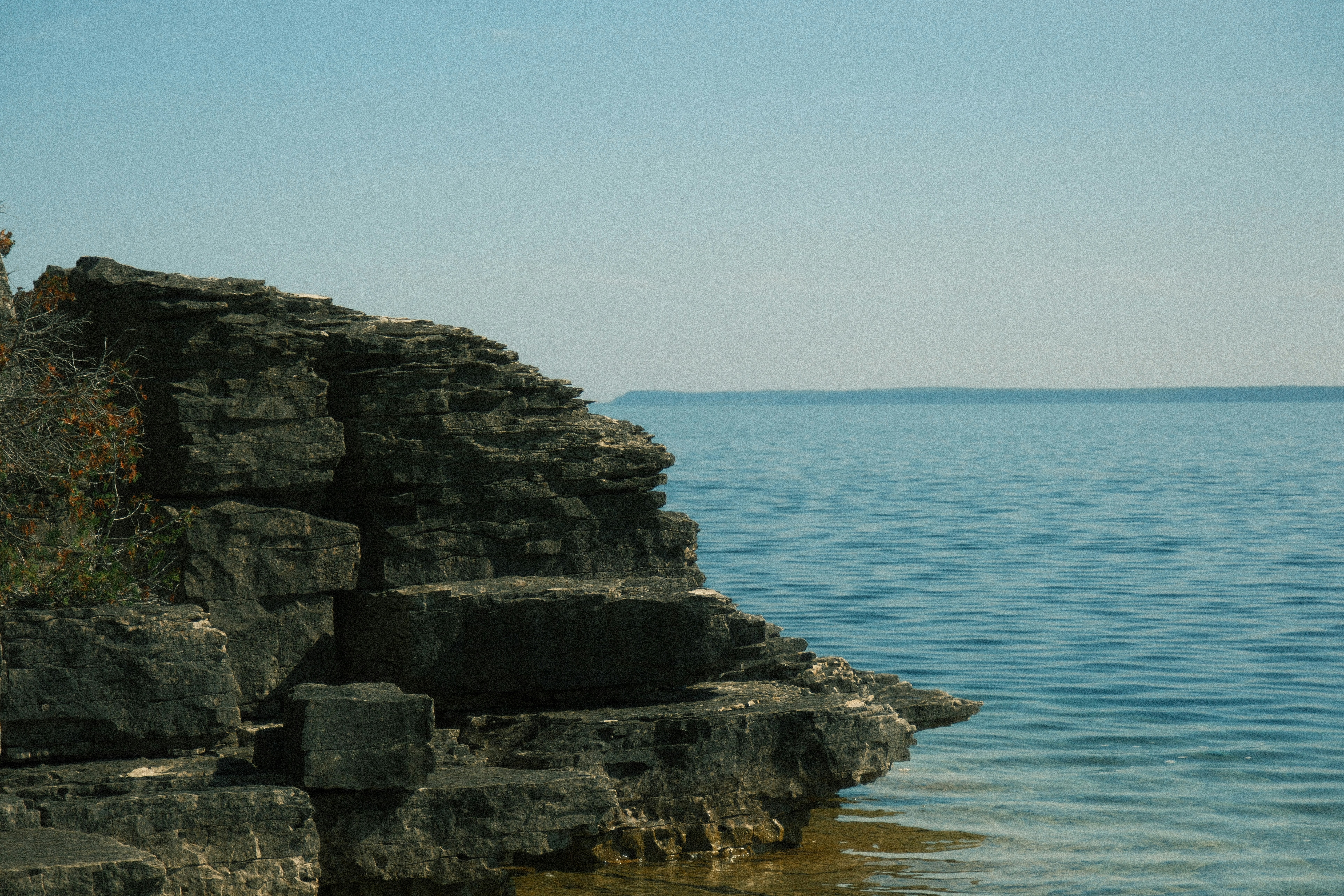 Strata at the Shoreline: Weathered Basalt Steps Meet a Quiet Sea
