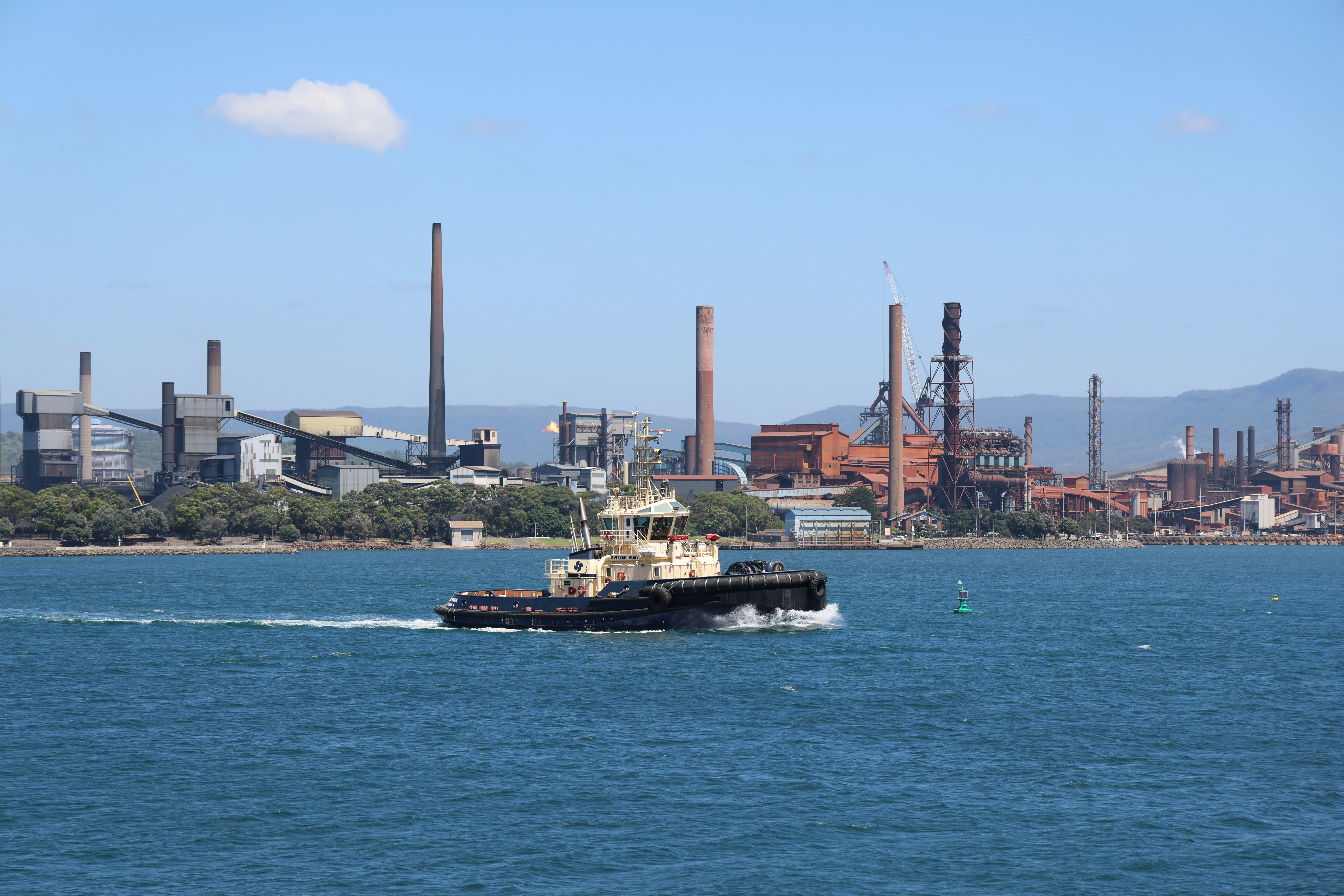 Tugboat in Service, Industrial Coastline Under Clear Sky