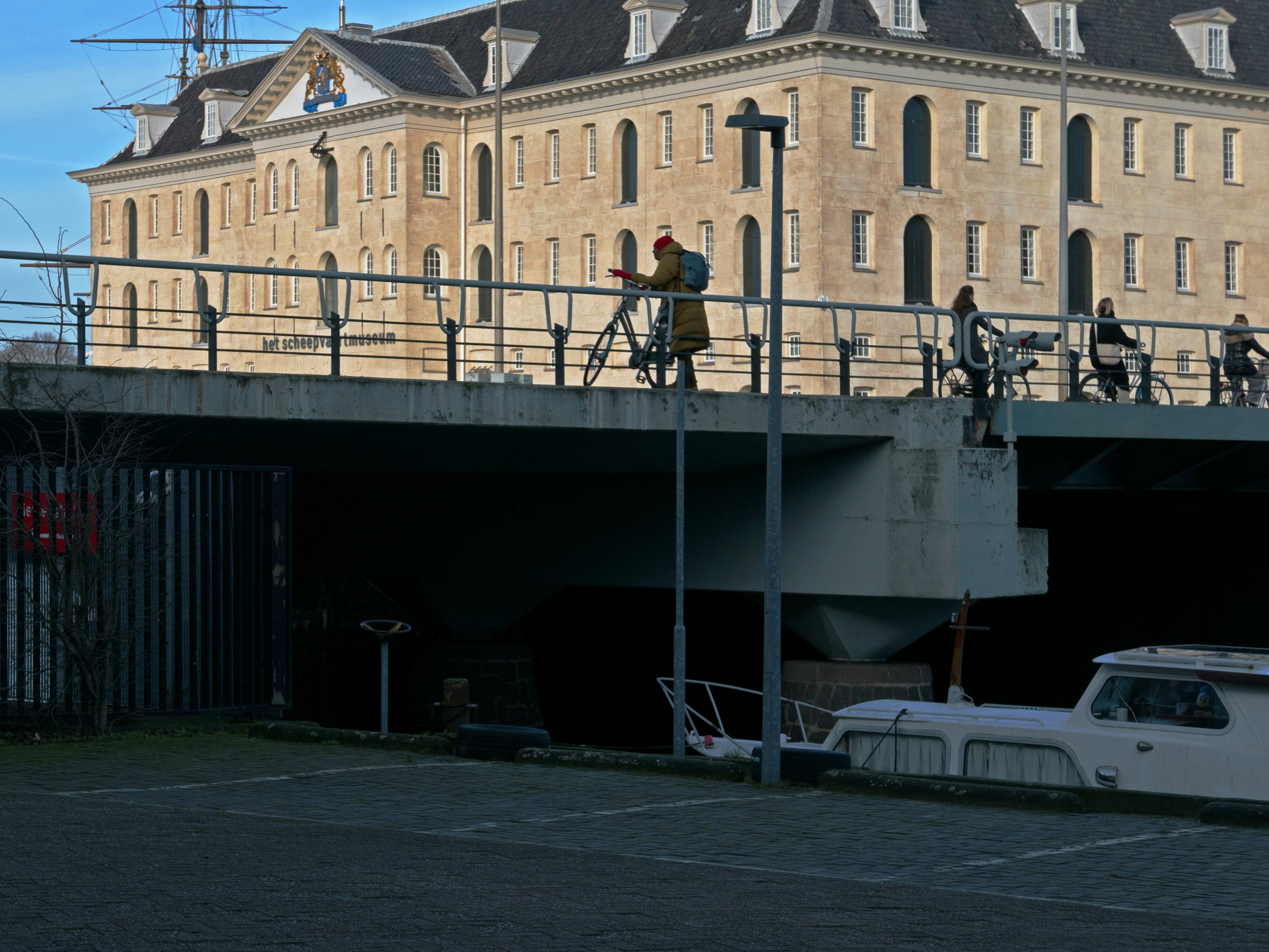 Crossing the Quiet Span: Cyclists on a Rail-Top Bridge Framed by a Brick Building