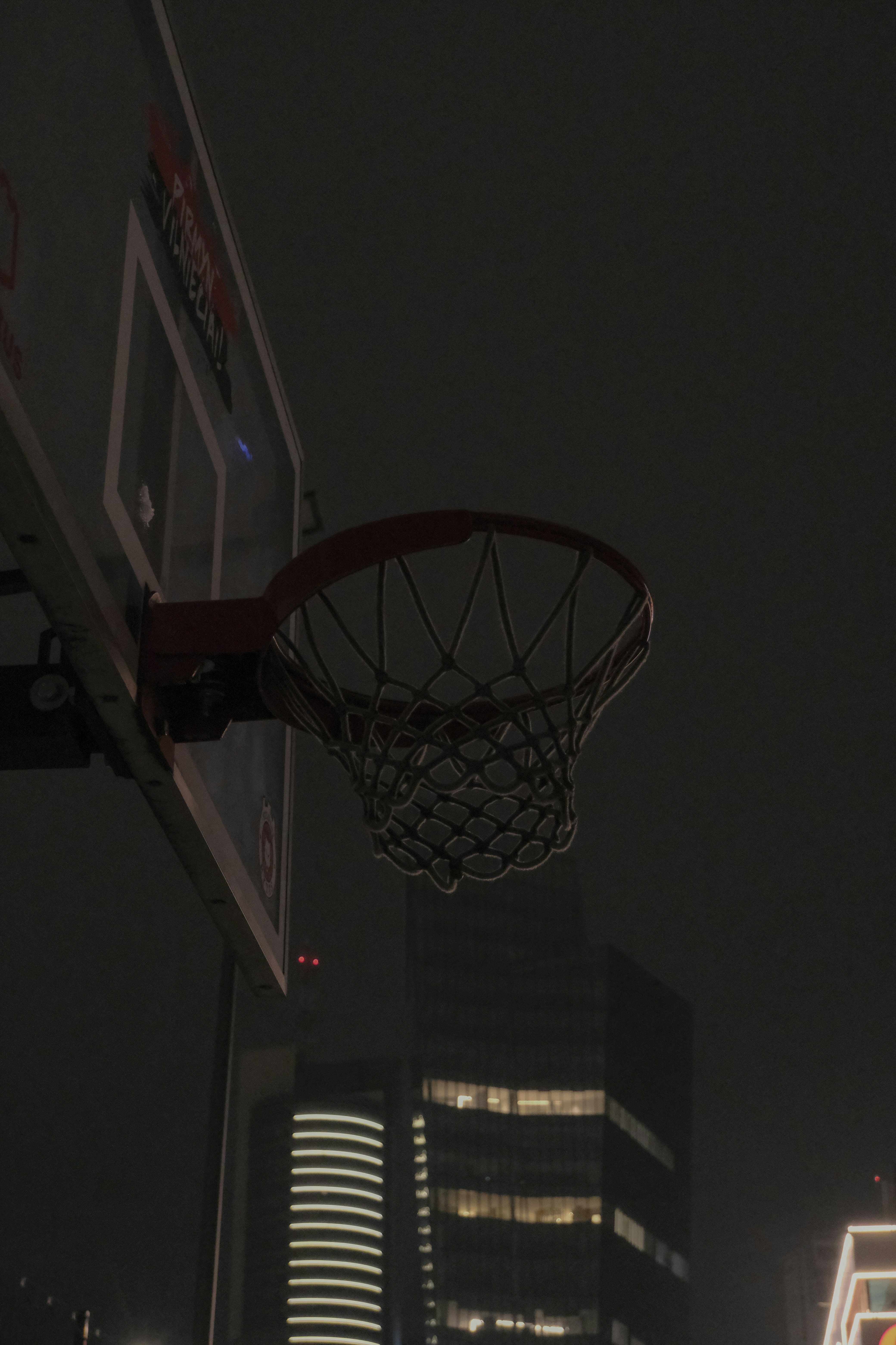 a basketball going through the hoop in a city at night