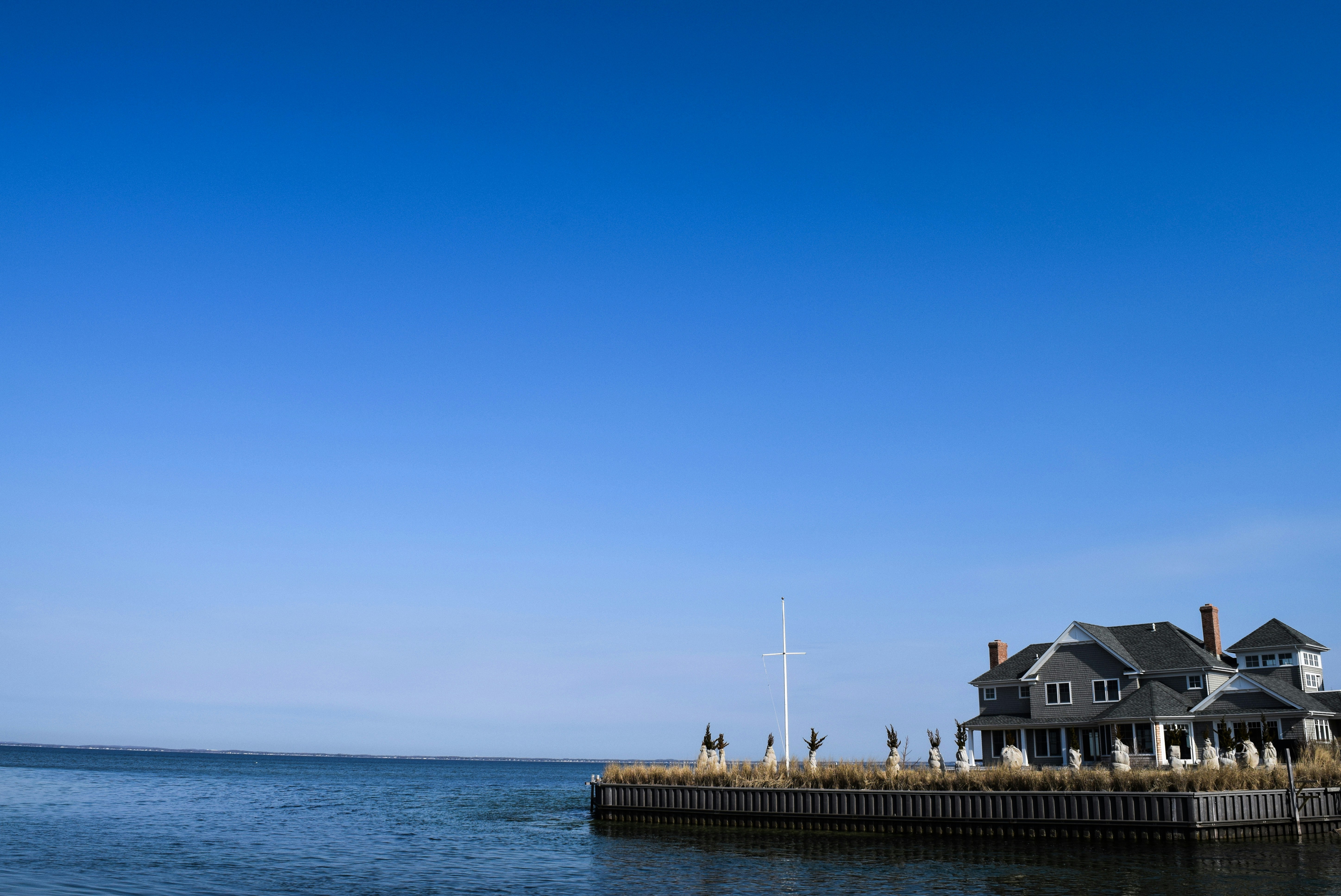 Seaside house on a pier under a vast blue sky and calm ocean waters.