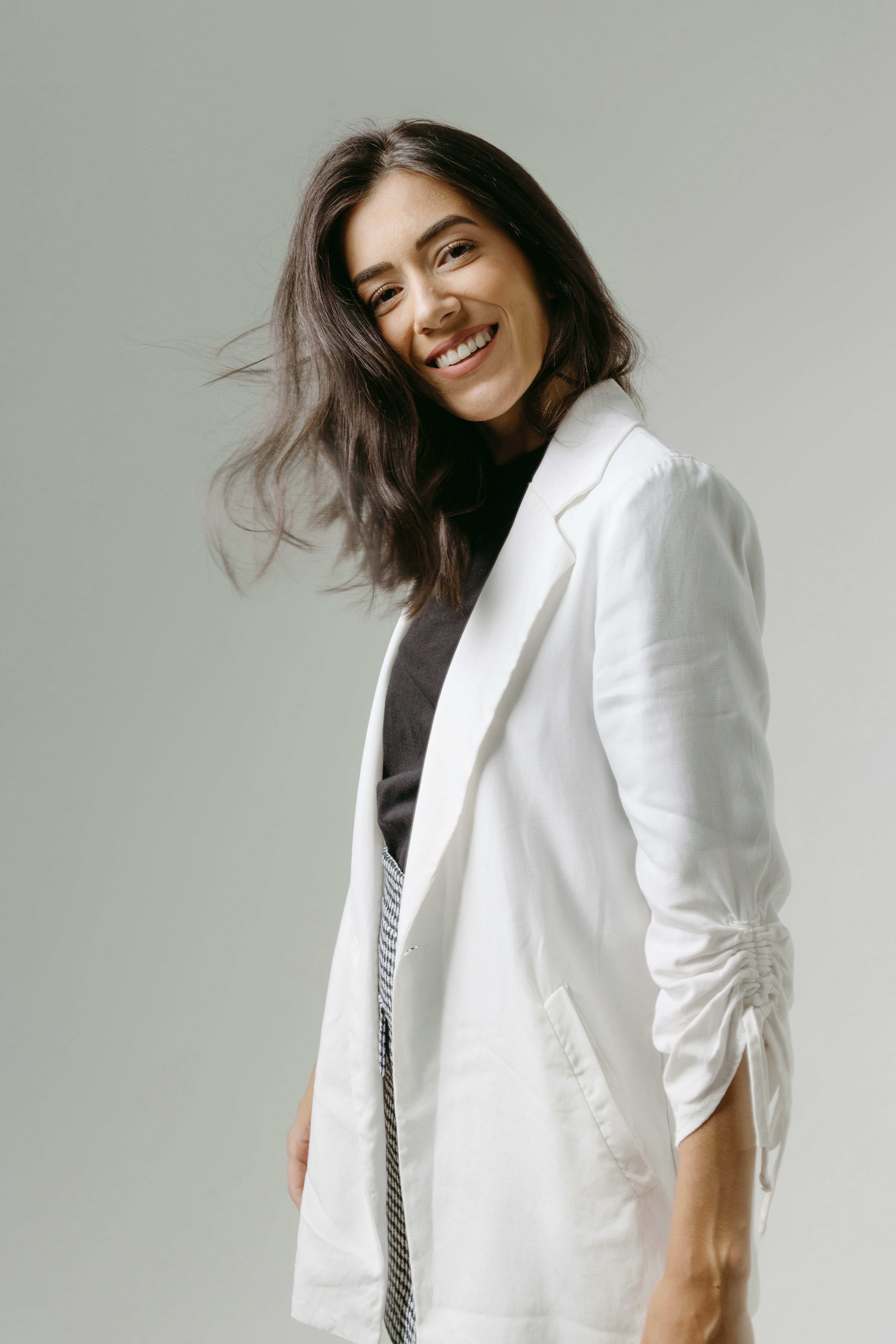 A woman in a white blazer smiles at the camera photo – Free Grey Image ...