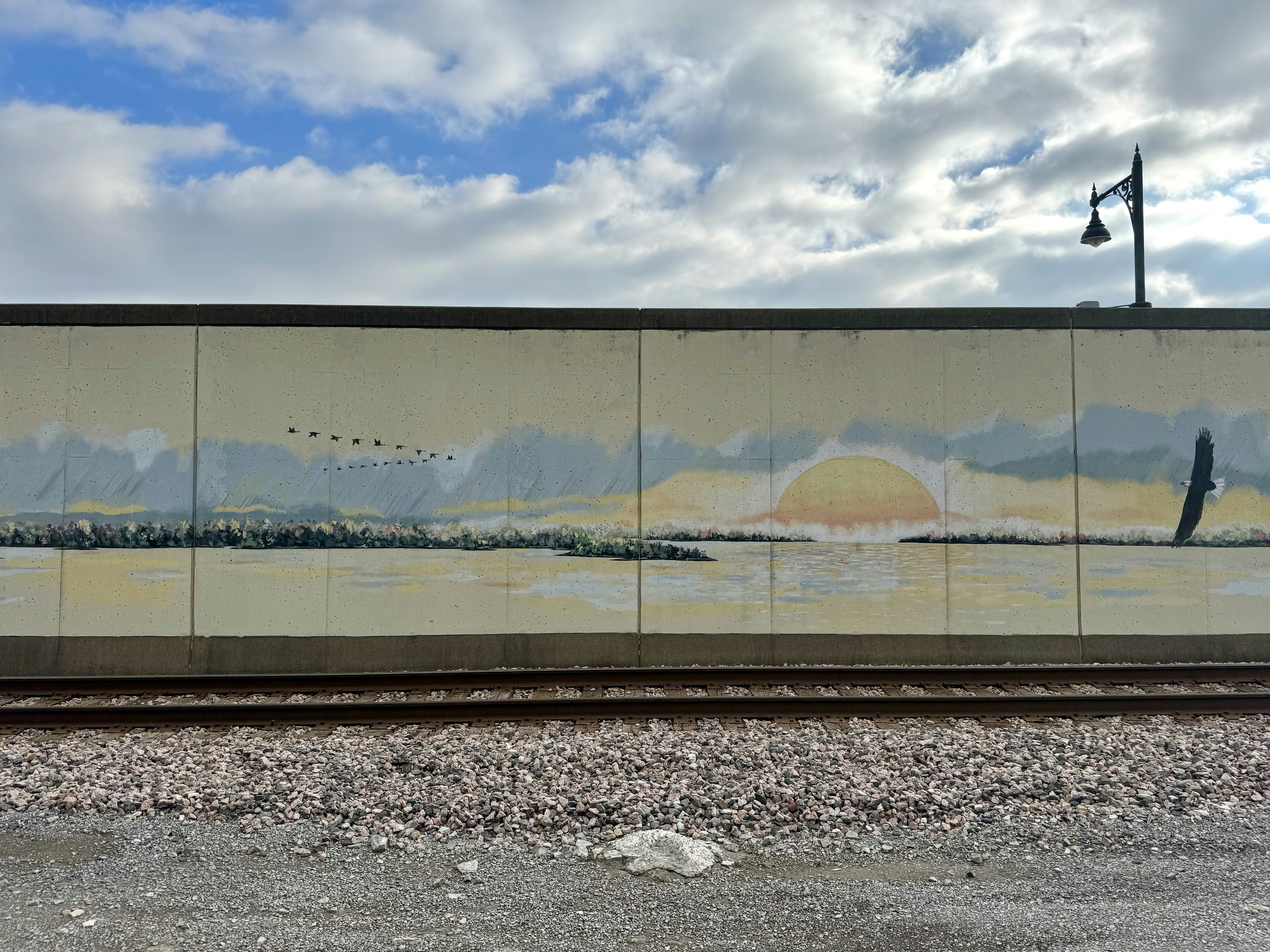 Sunset over the Painted Barrier: A Rail-Side Mural at Dusk