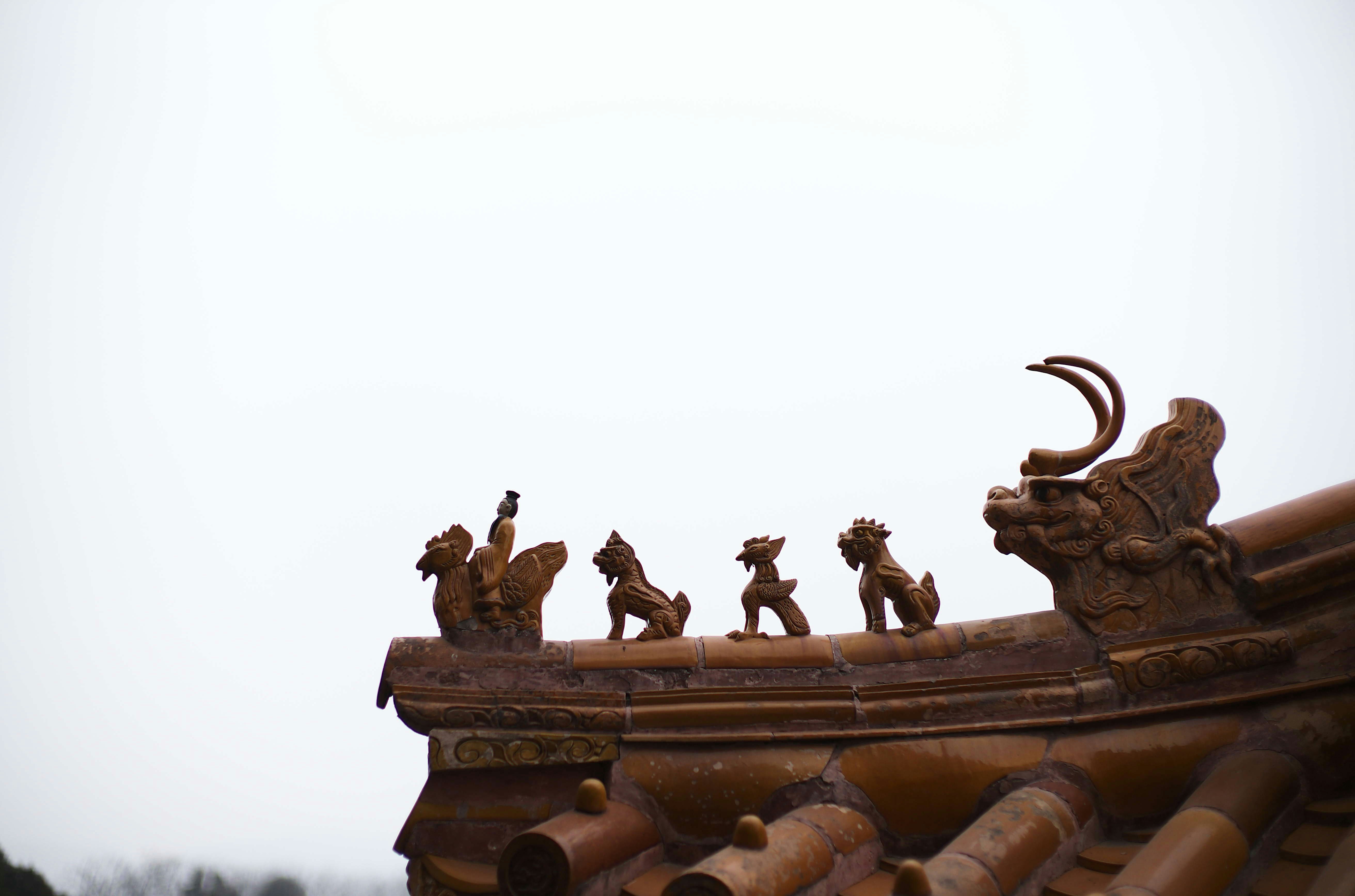 Roofline Ornaments: Tiny Ceremonial Figures Silhouetted Against Sky