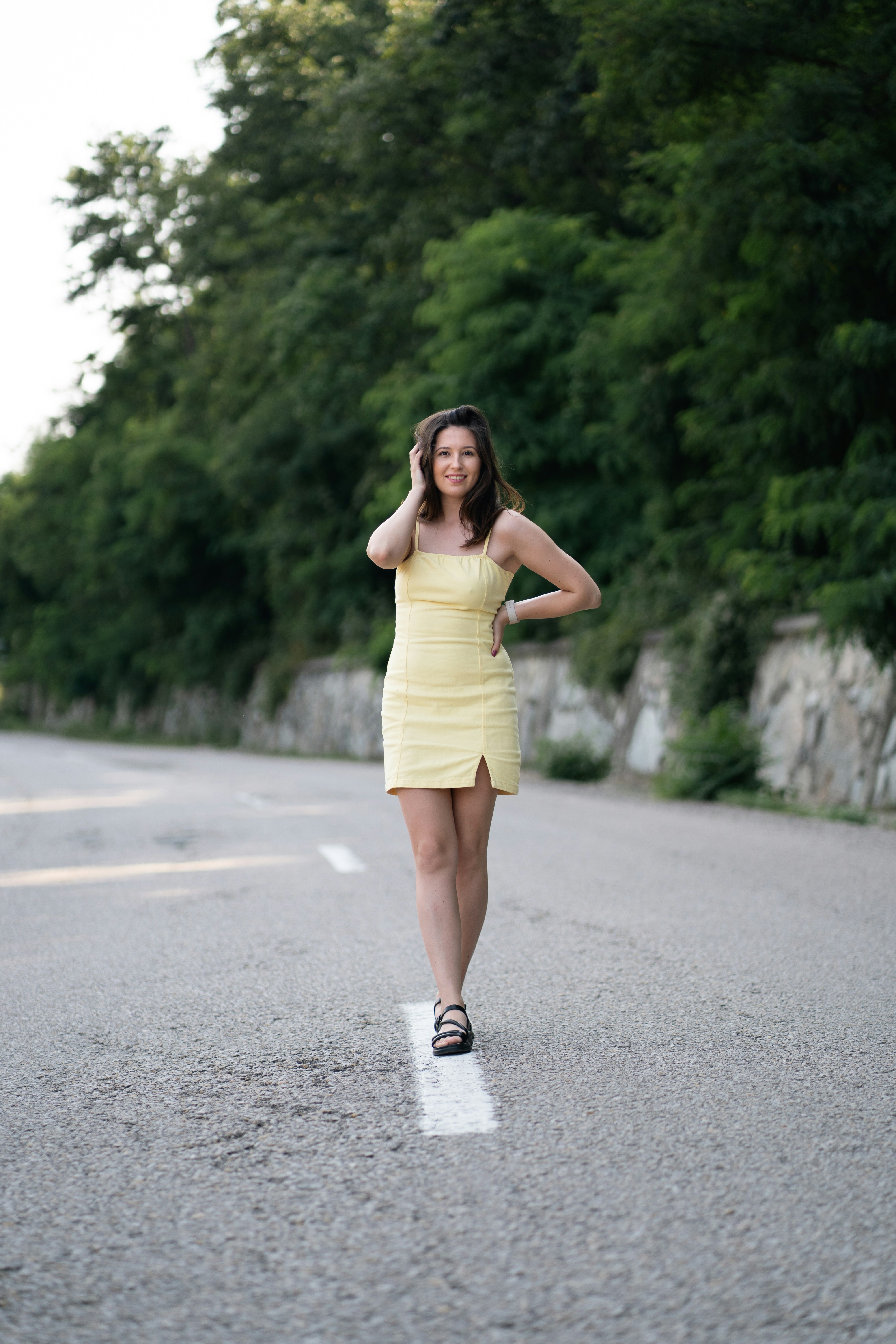 Golden Hour Portrait: Woman in Yellow Dress on a Quiet Tree-Lined Road
