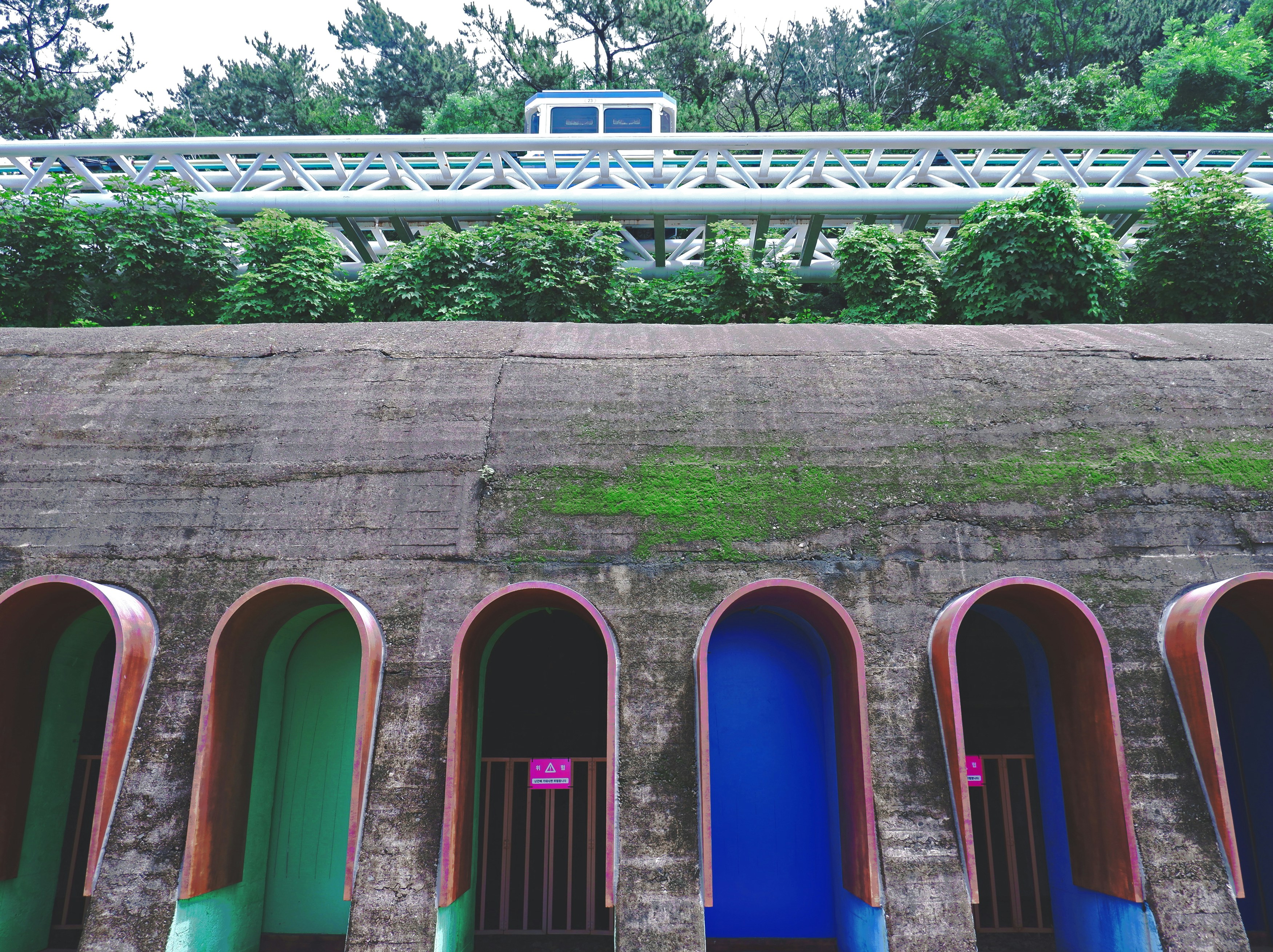 A row of blue, green, and red toilets next to a bridge photo – Free ...