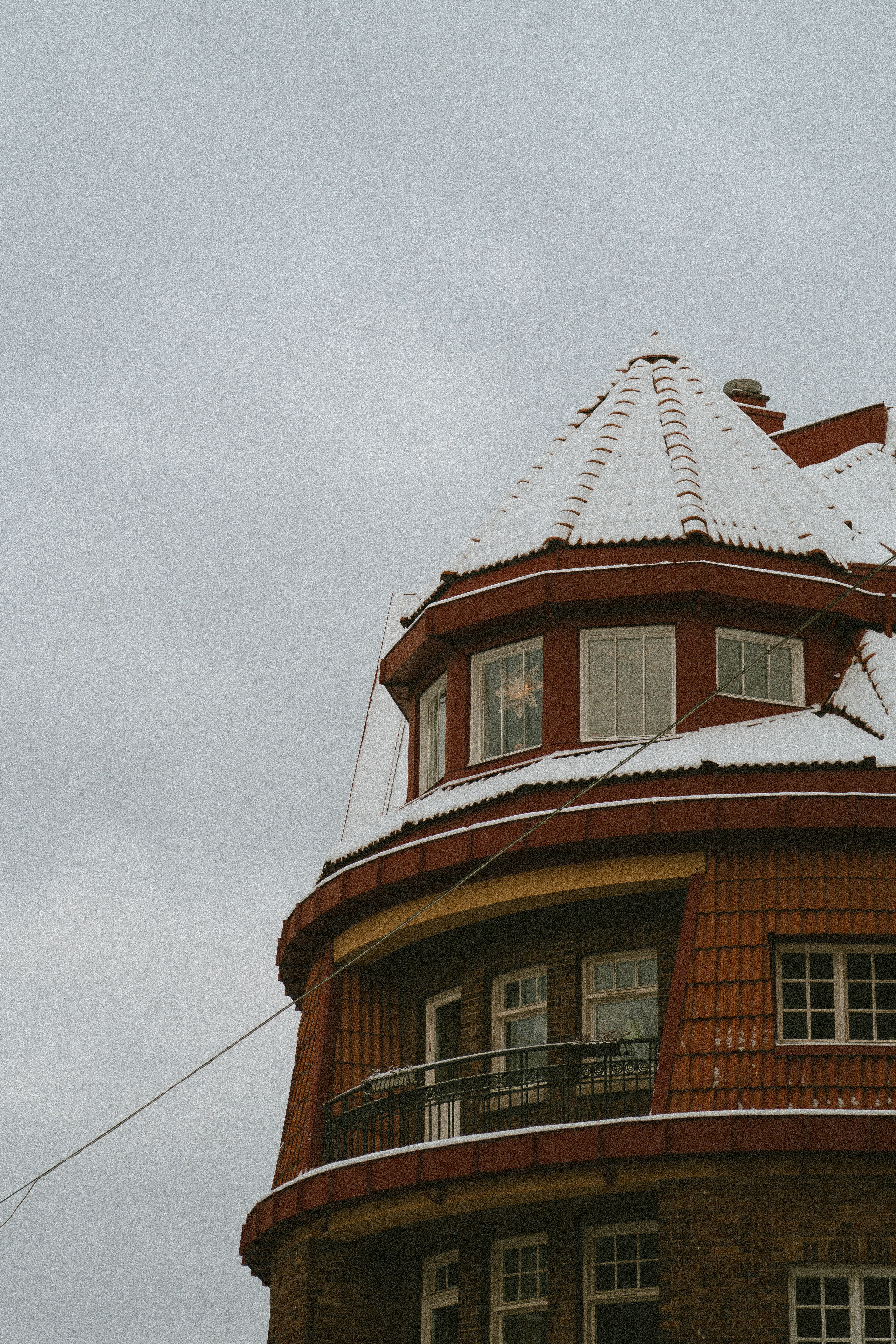 Snow-dusted turreted brick dwelling against a moody gray sky
