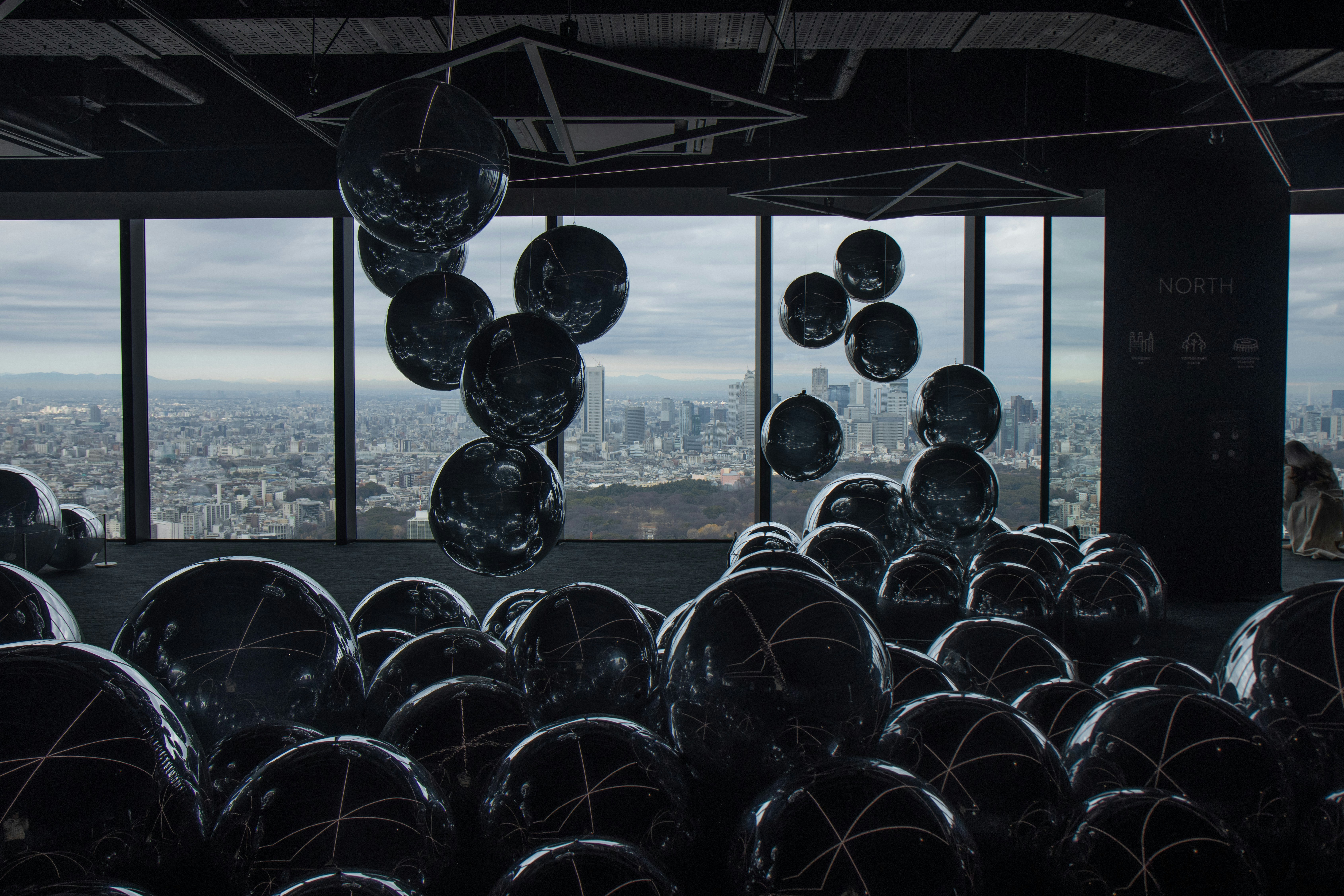 Obsidian Orbs Framing the Skyline in a Sphere-Laden Atrium