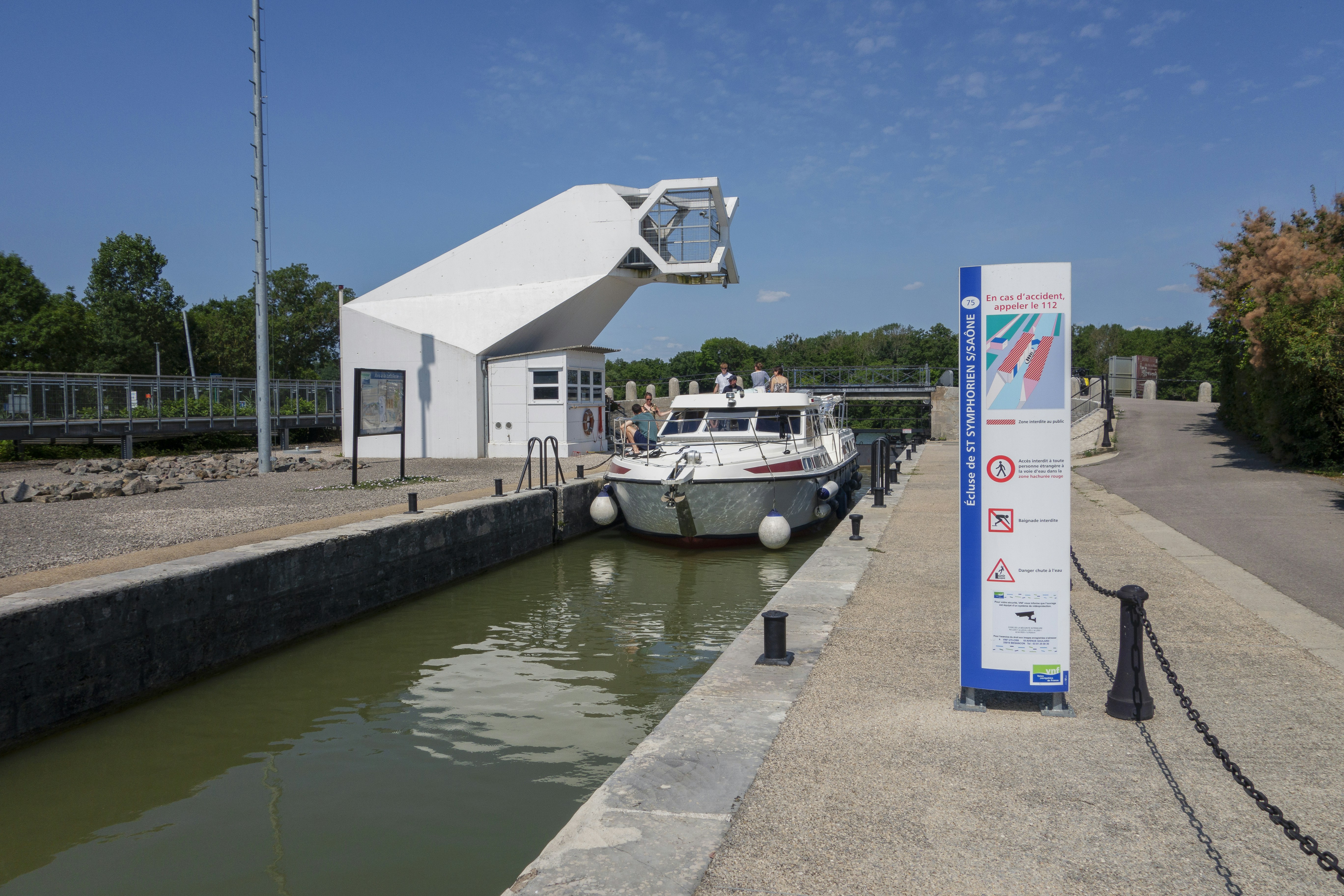 Canal Geometry: A Boat Beside a Bold White Shelter and Promenade Sign