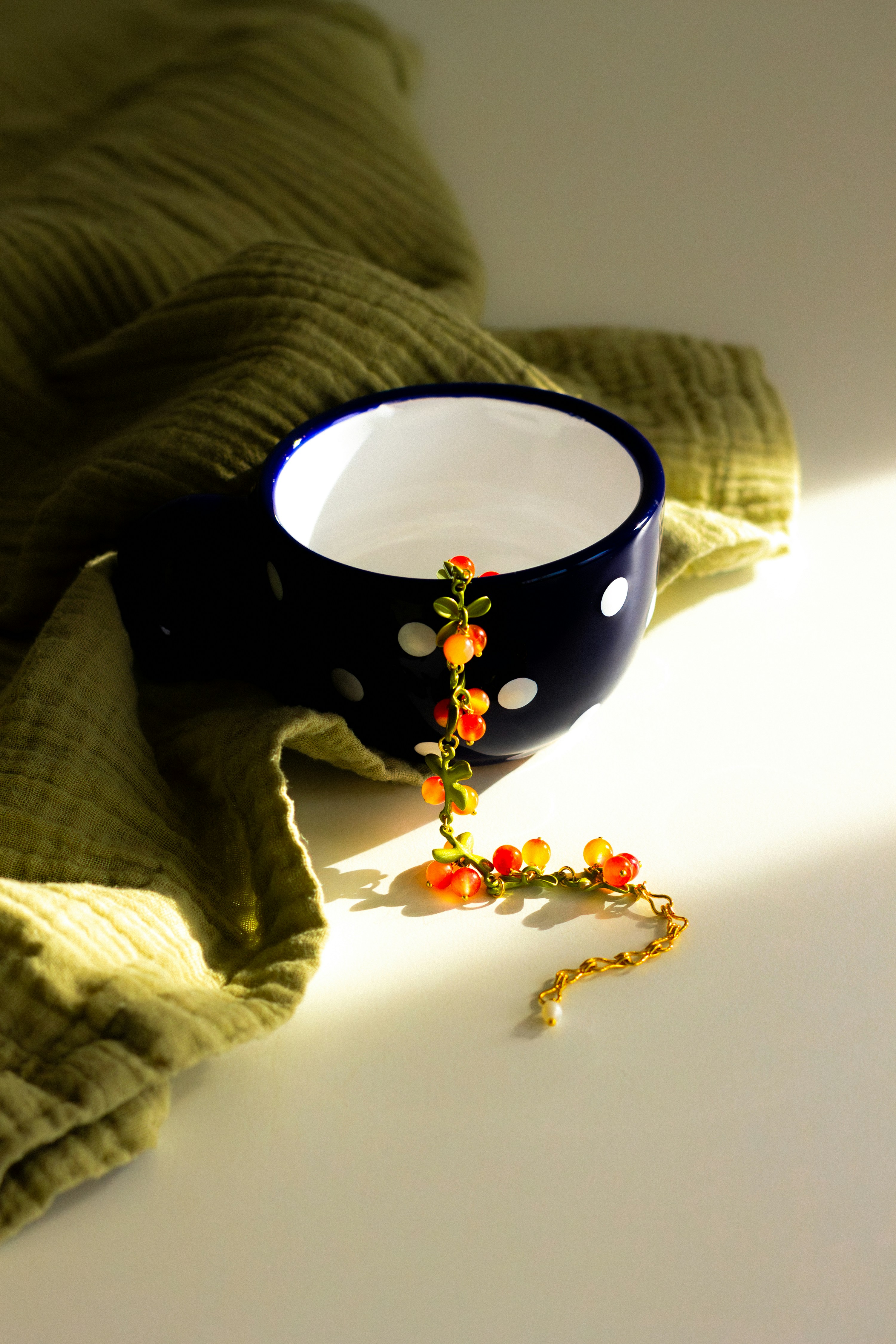 Polka-Dot Mug Embraced by Golden Light and a Coral Bead Vine