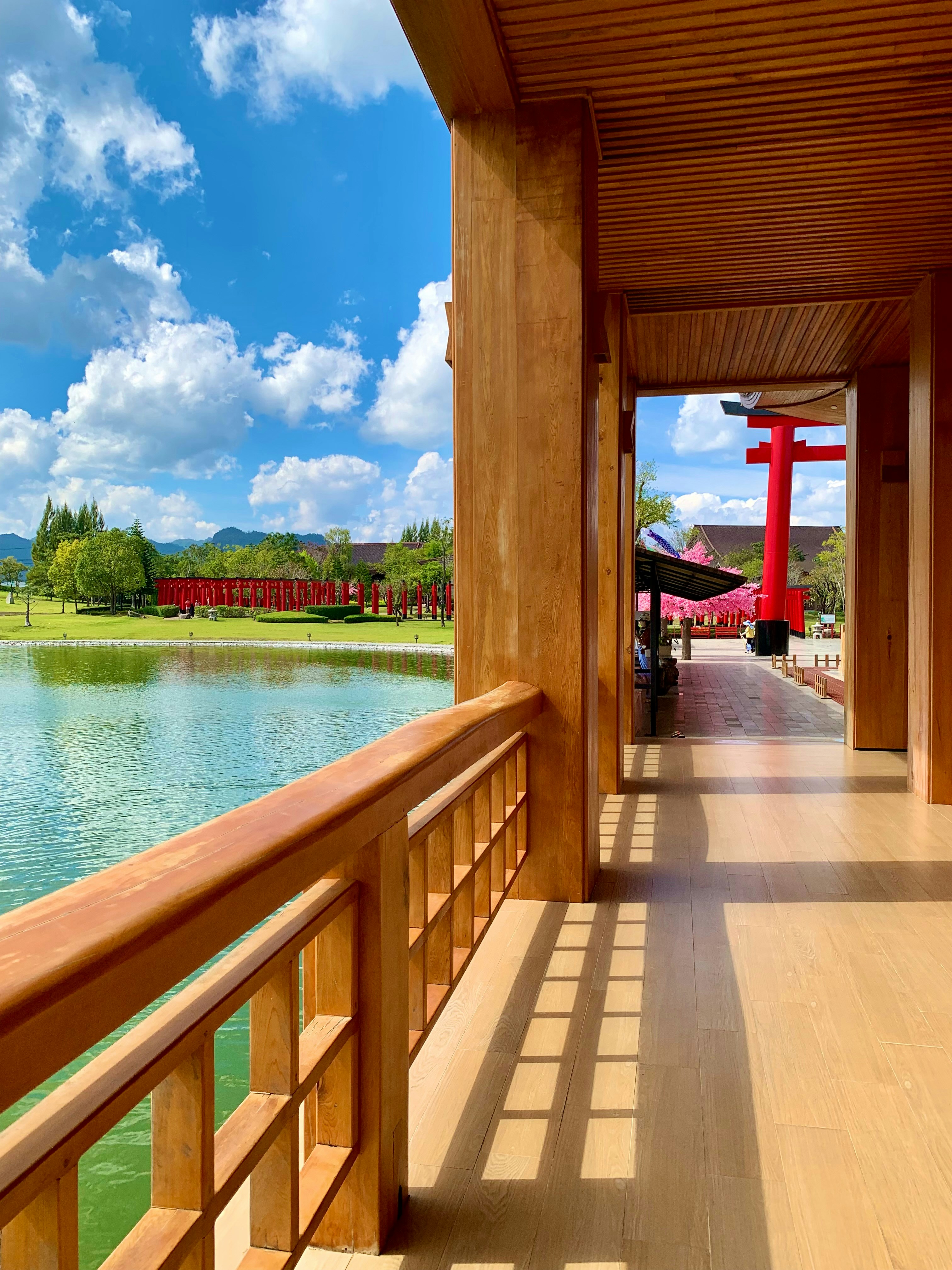 Veranda Toward a Red Torii: Sunlit Walkway by a Tranquil Lake