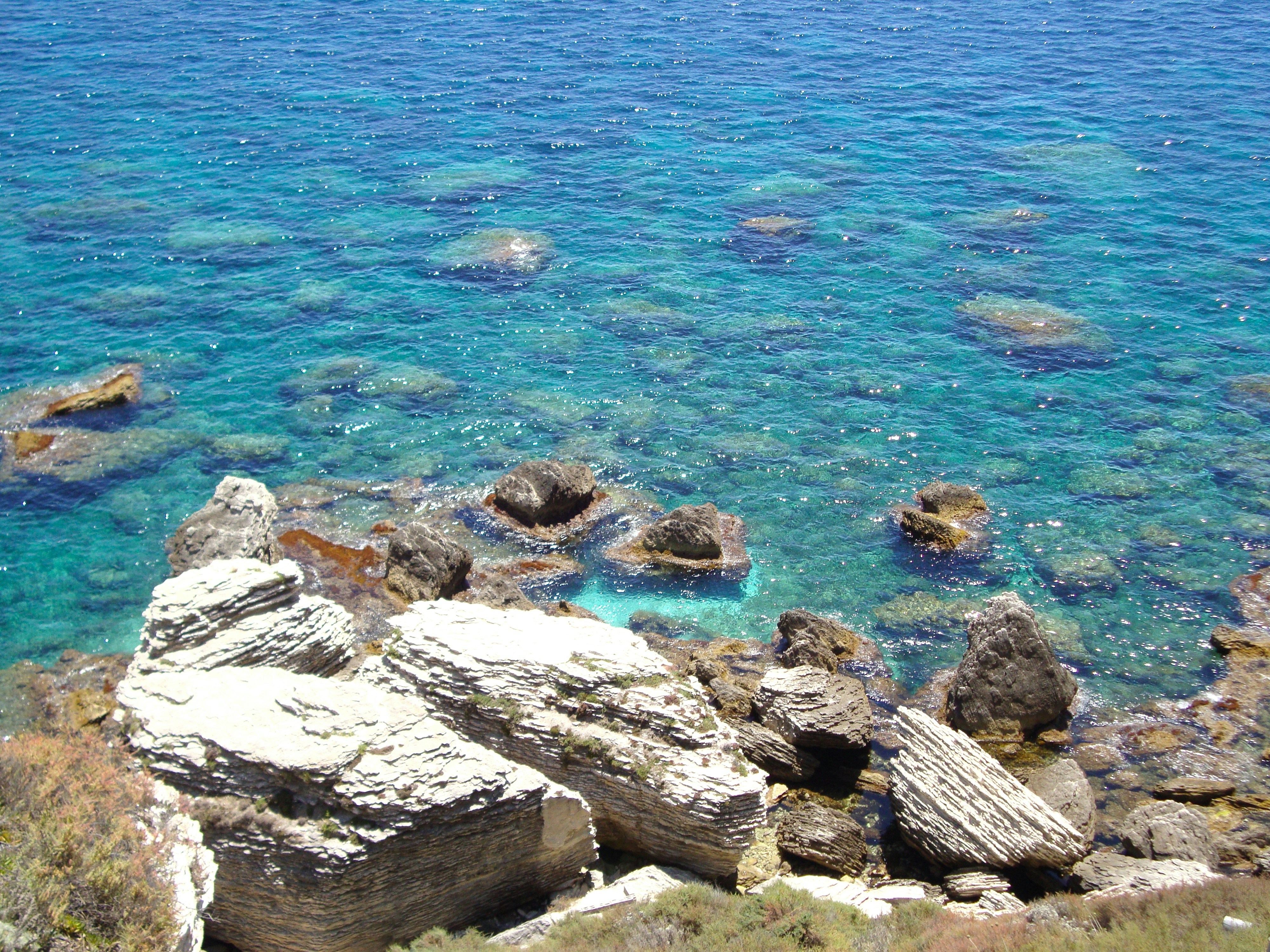 A body of water surrounded by rocks and grass photo – Free Corsica ...