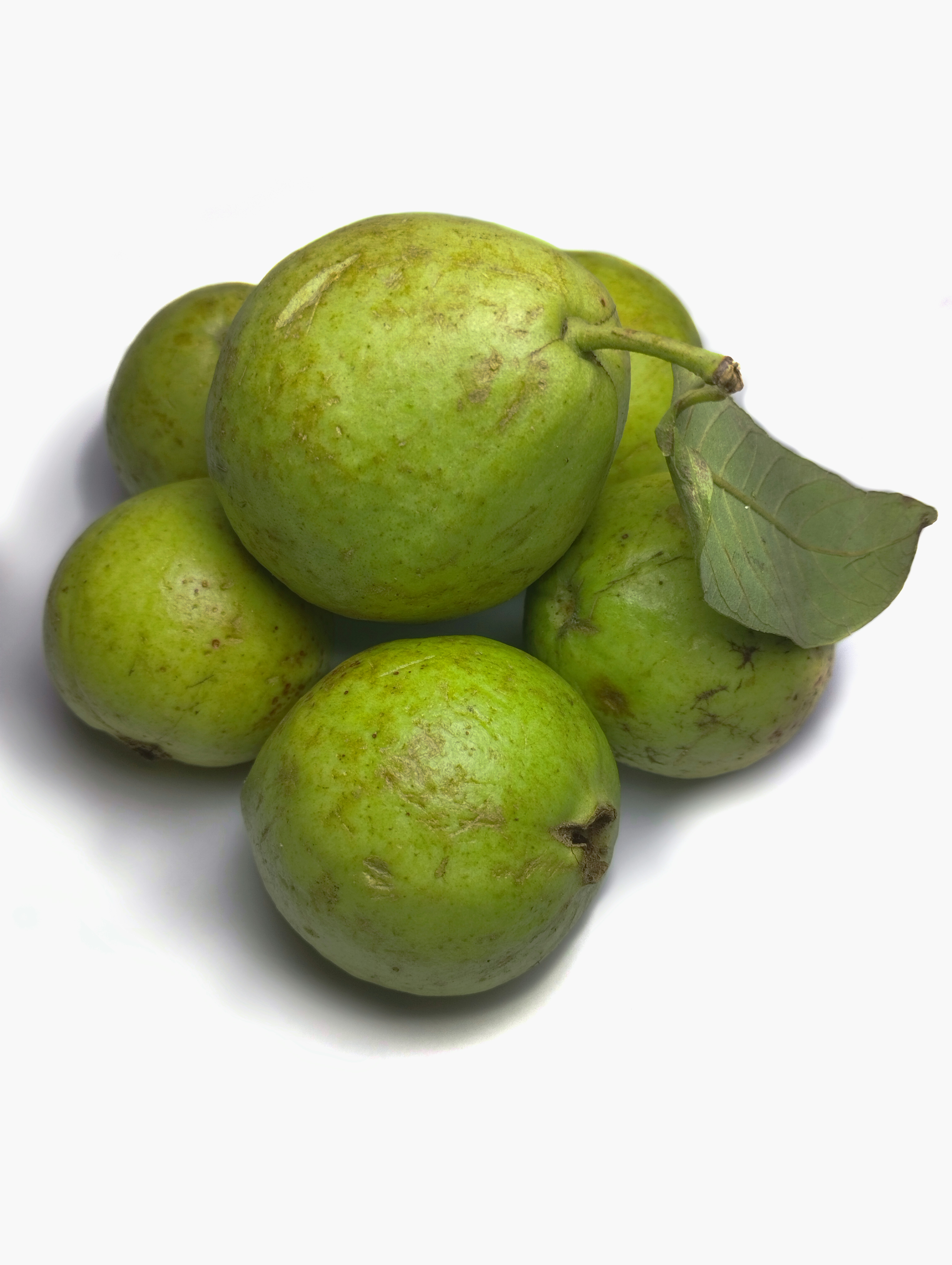 A still-life photograph of several green pears stacked with a leaf on a bright white background.