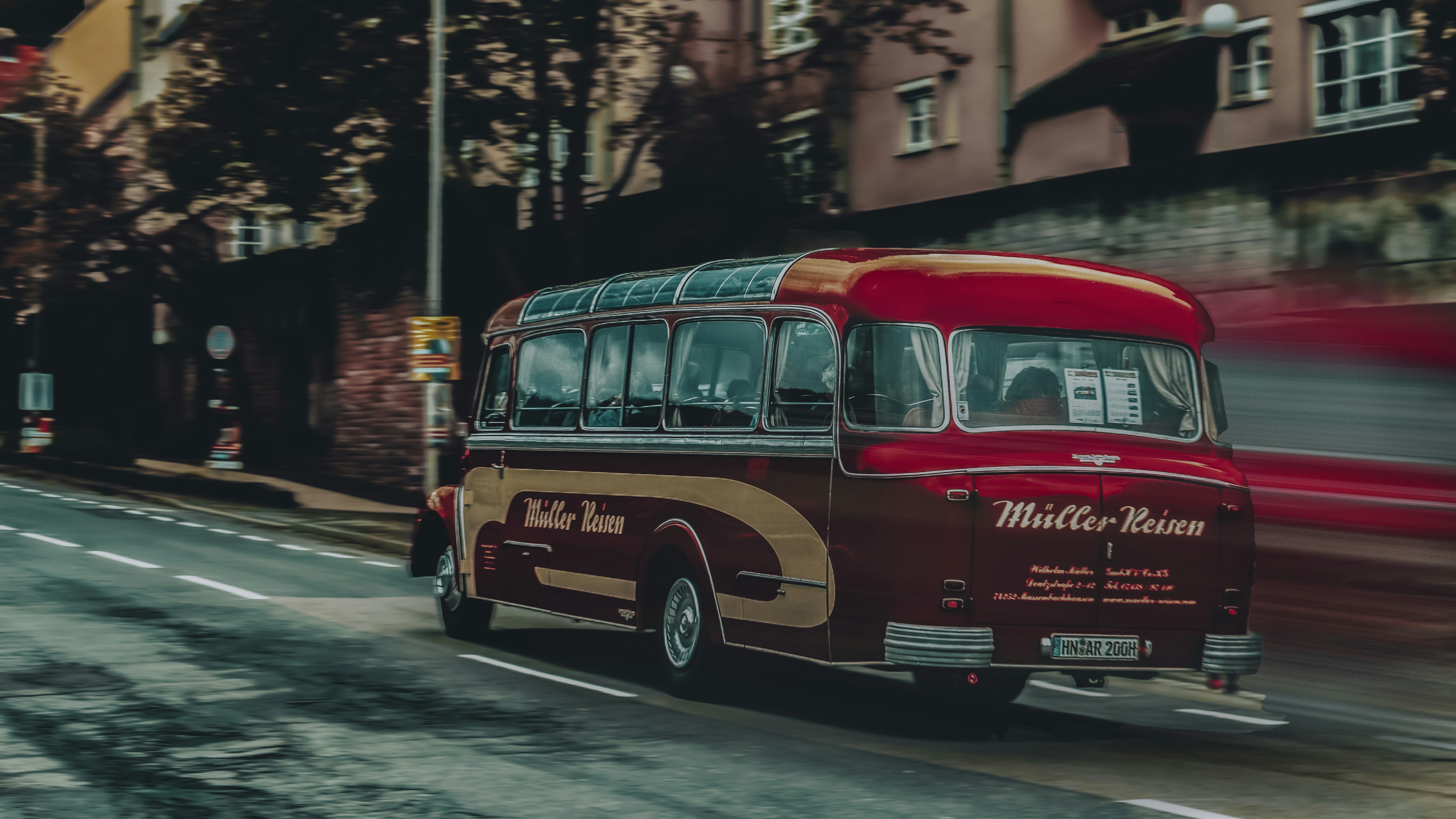 A red bus driving down a street next to tall buildings photo – Free Bus ...