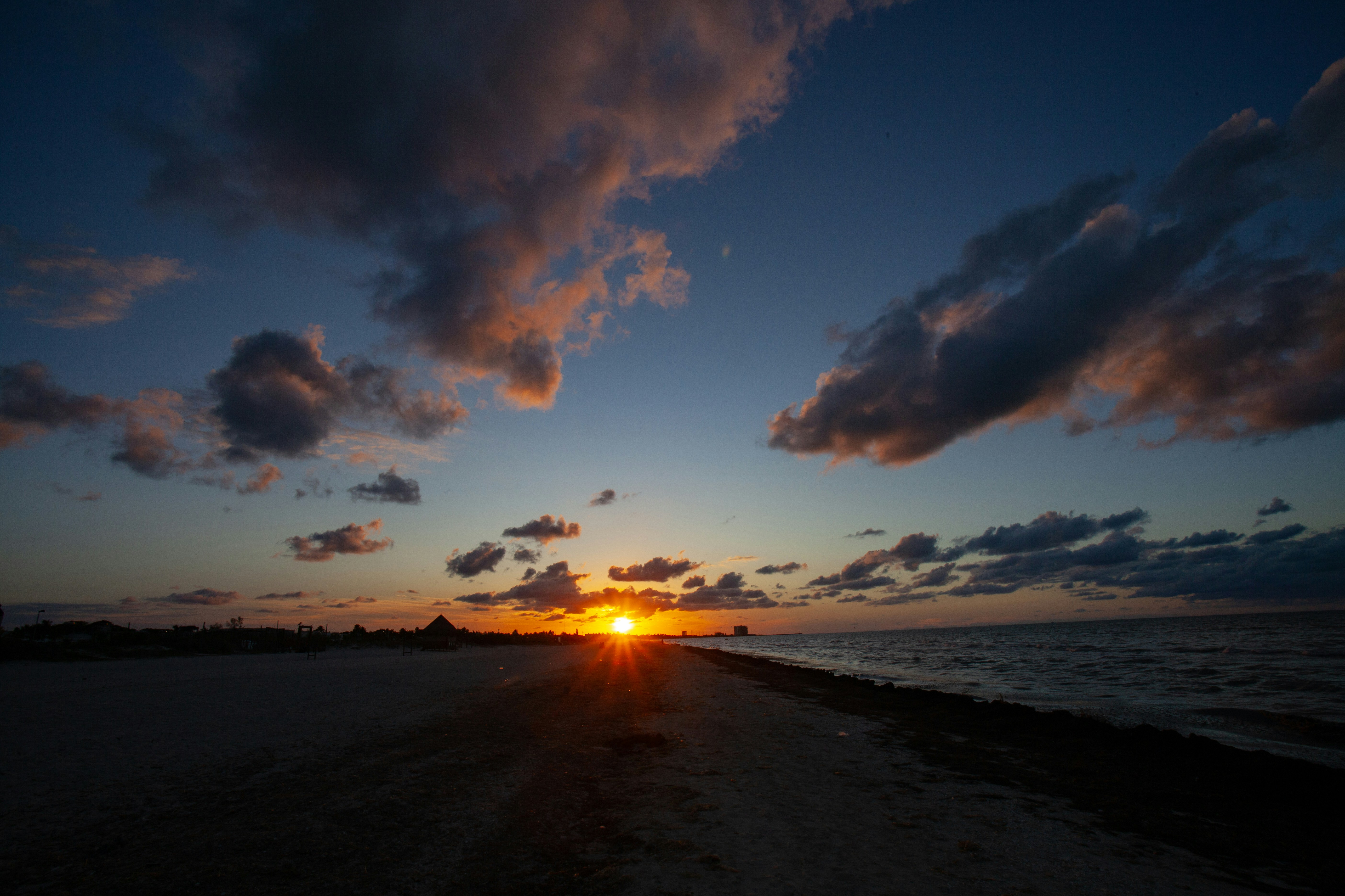 Horizon Ember on a Quiet Beach: Sunset Light Weaving Through Clouds
