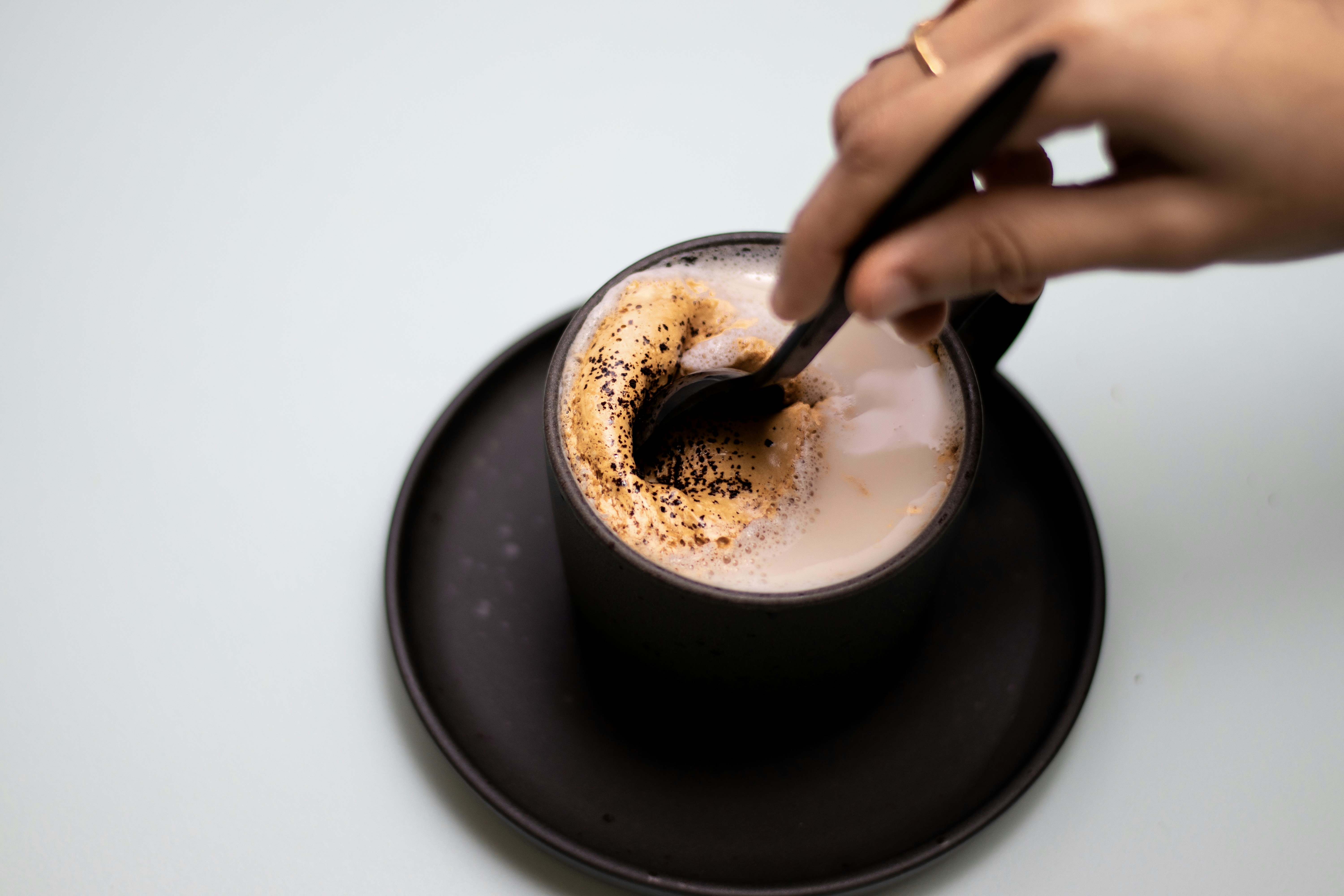 A person stirring a cup of coffee with a spoon photo – Free Salalah ...