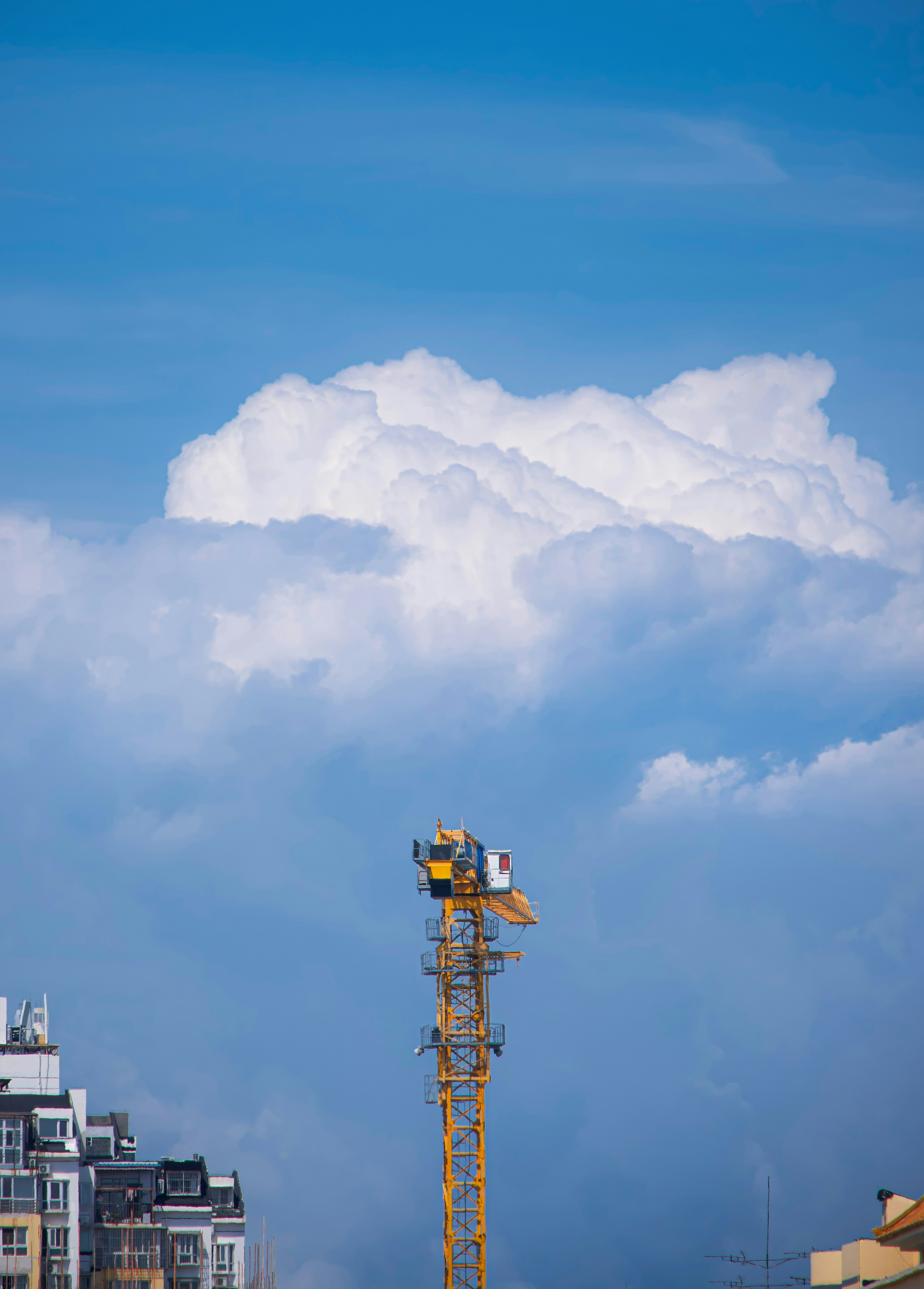 Towering Yellow Crane Against a Cloud-Washed Cityscape