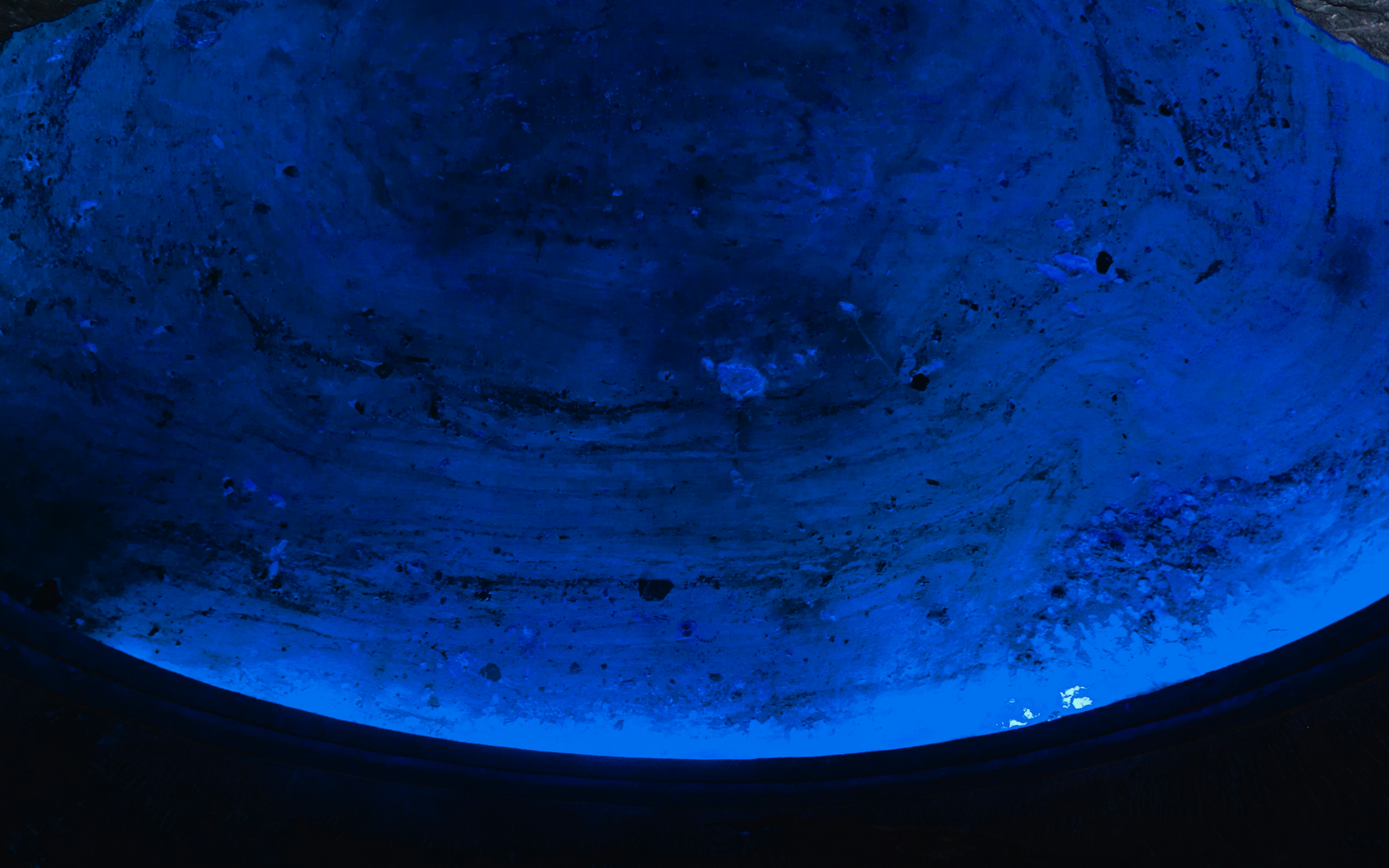 Blue-lit circular interior with a glowing rim creates an abstract moody photograph.