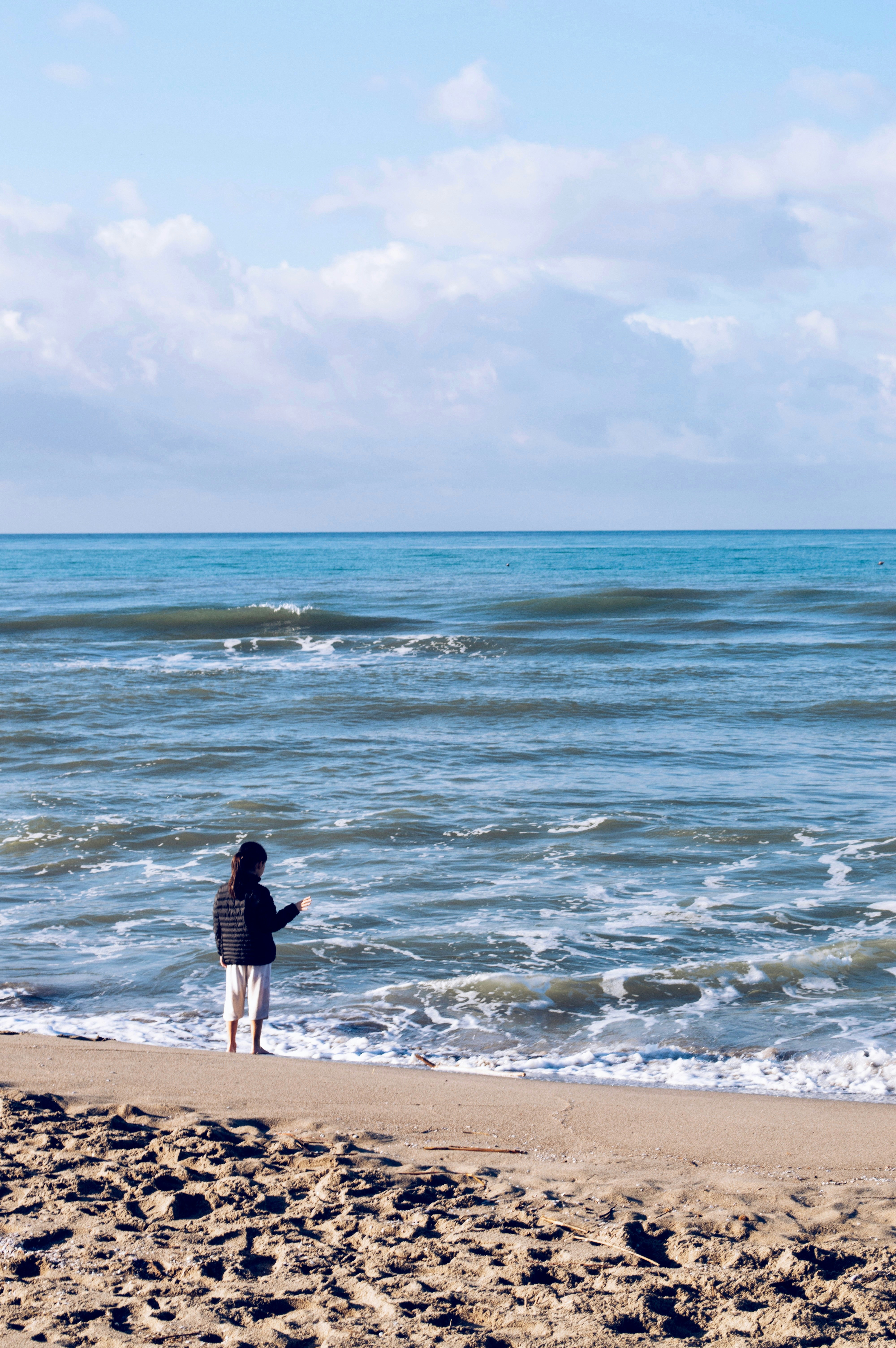 Edge of the Quiet Sea: A Lone Beach Walker Under Open Sky