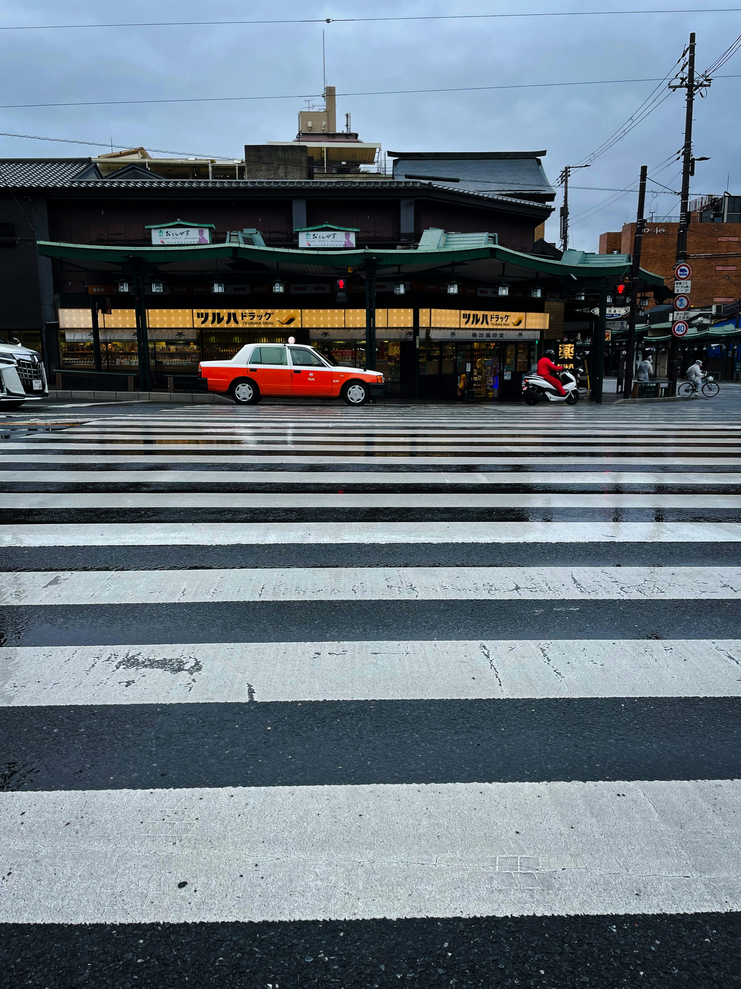Red Taxi at a Rain-Washed Zebra Crossing