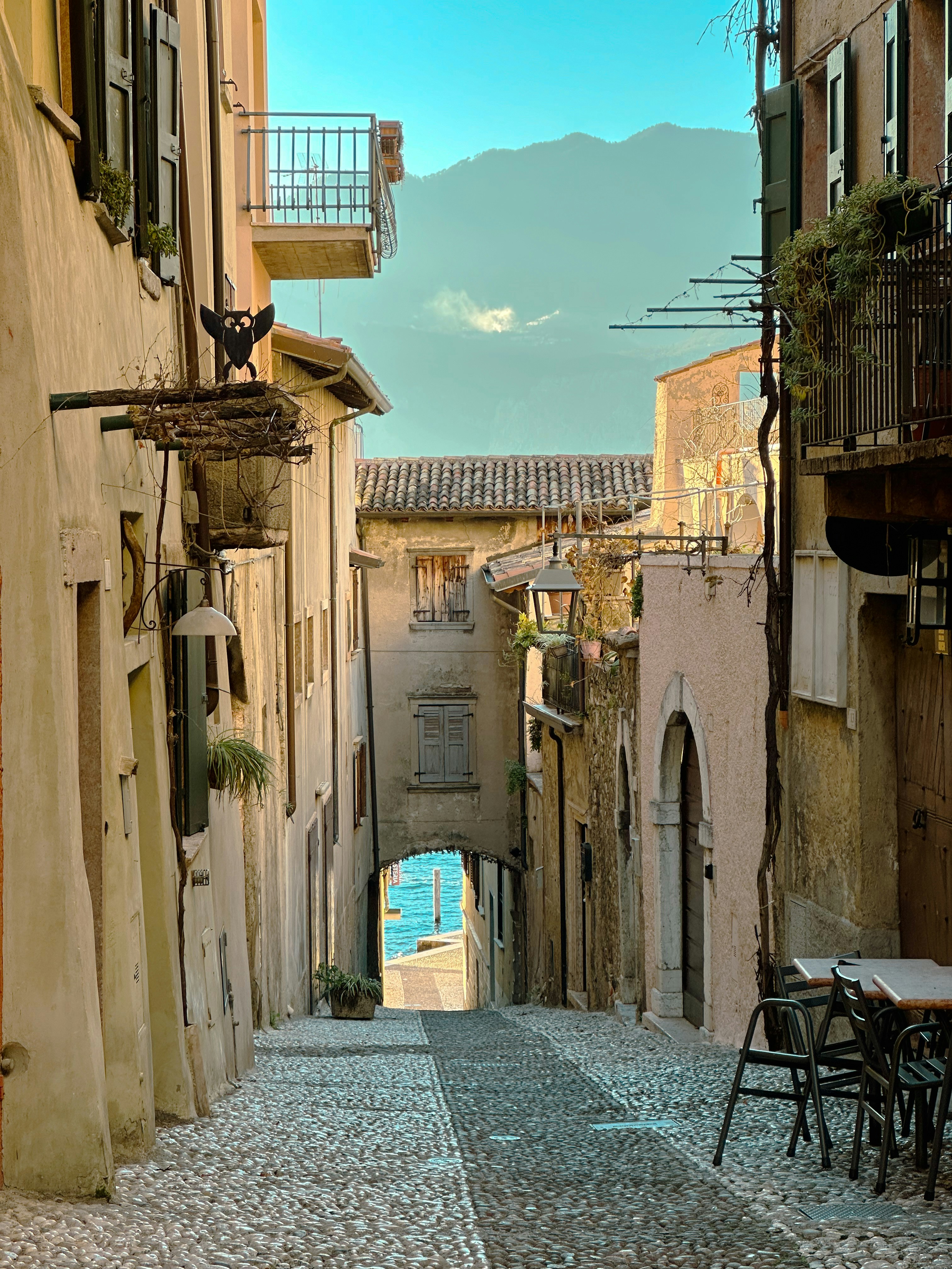 a cobblestone street with tables and chairs on either side