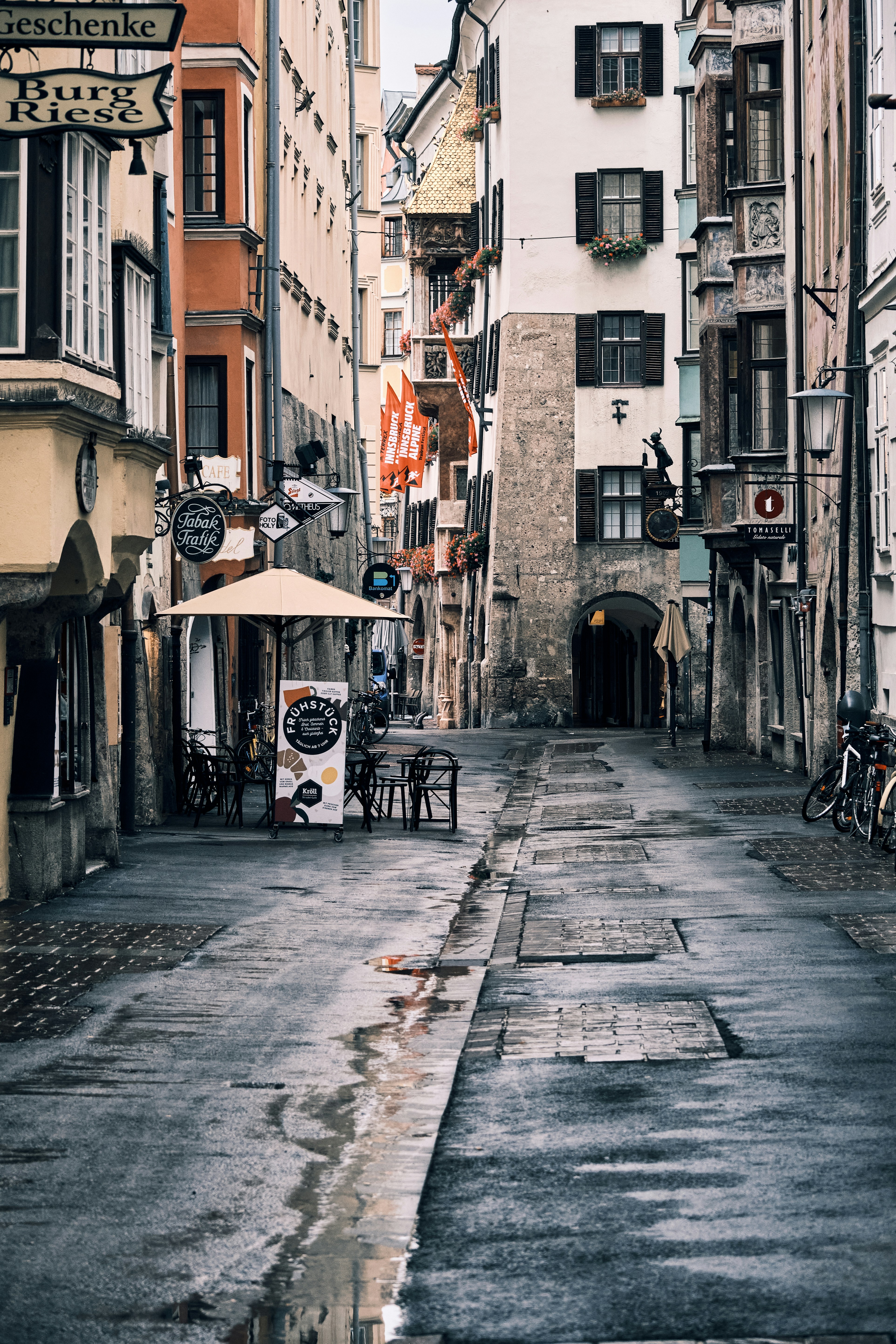 A narrow city street with tables and umbrellas photo – Free Innsbruck ...