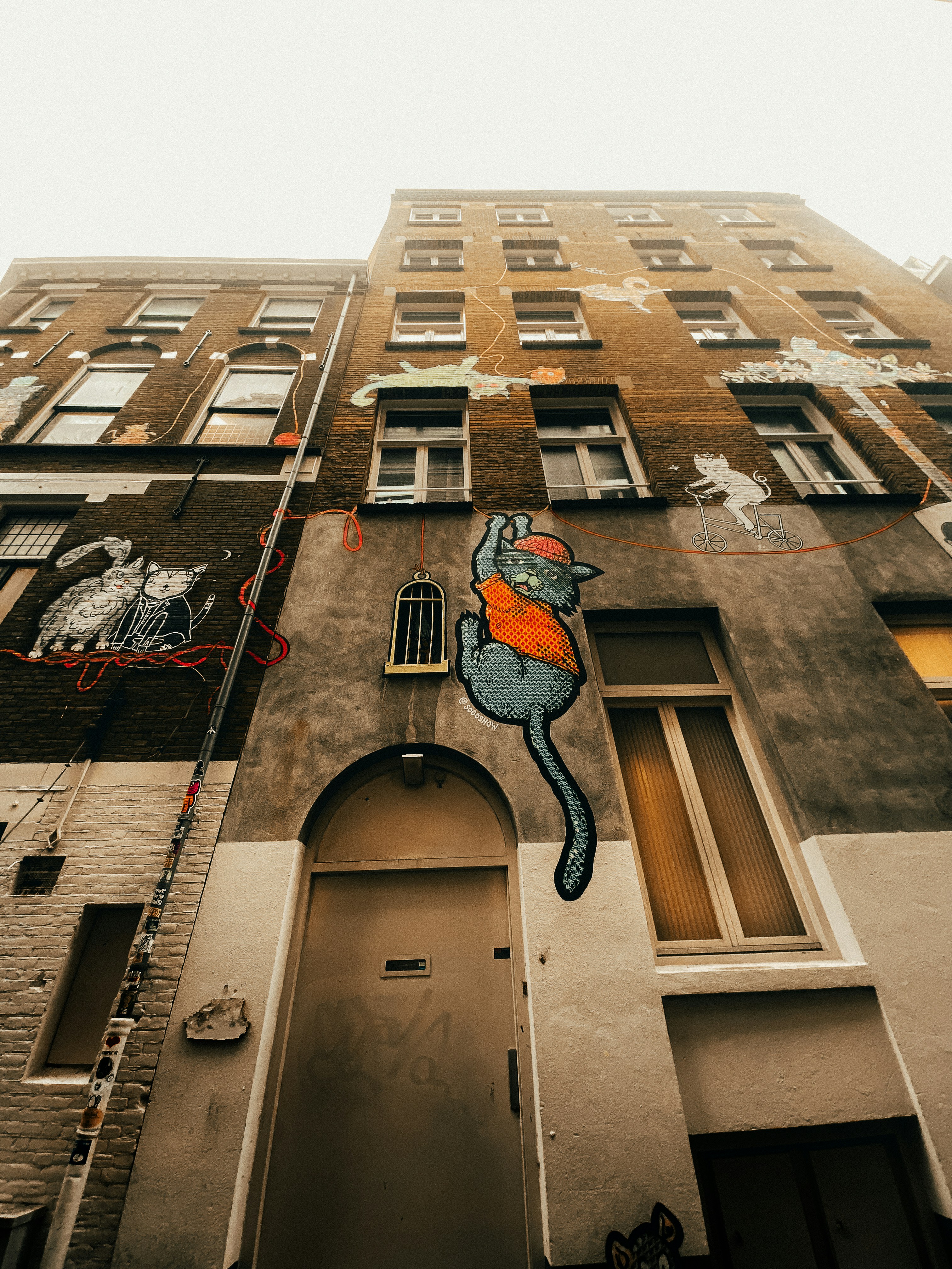 Climbing Blue Cartoon on a Weathered Brick Facade