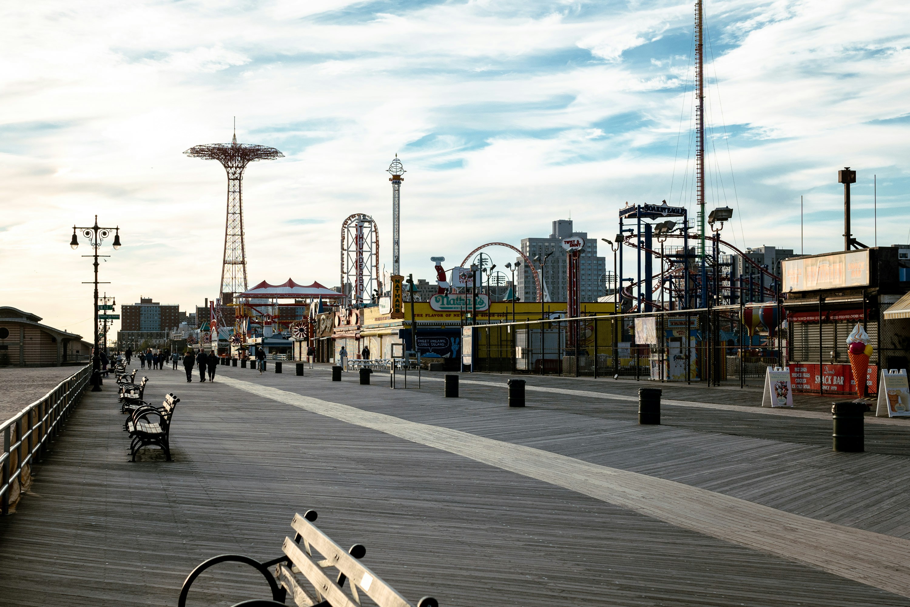 A boardwalk with benches and a roller coaster in the background photo ...