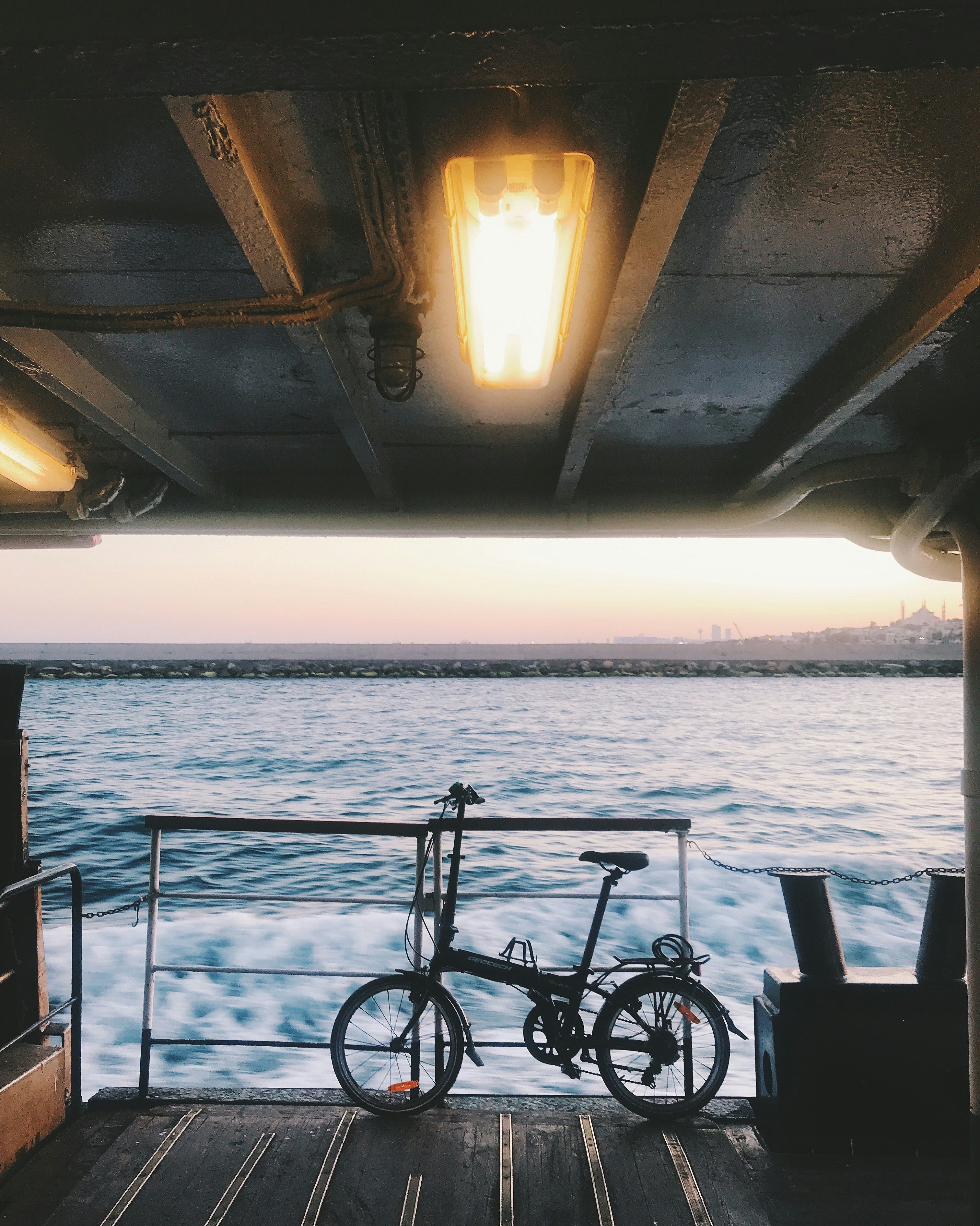 Dusk on the Deck: a Bicycle Framed by Water and Rail