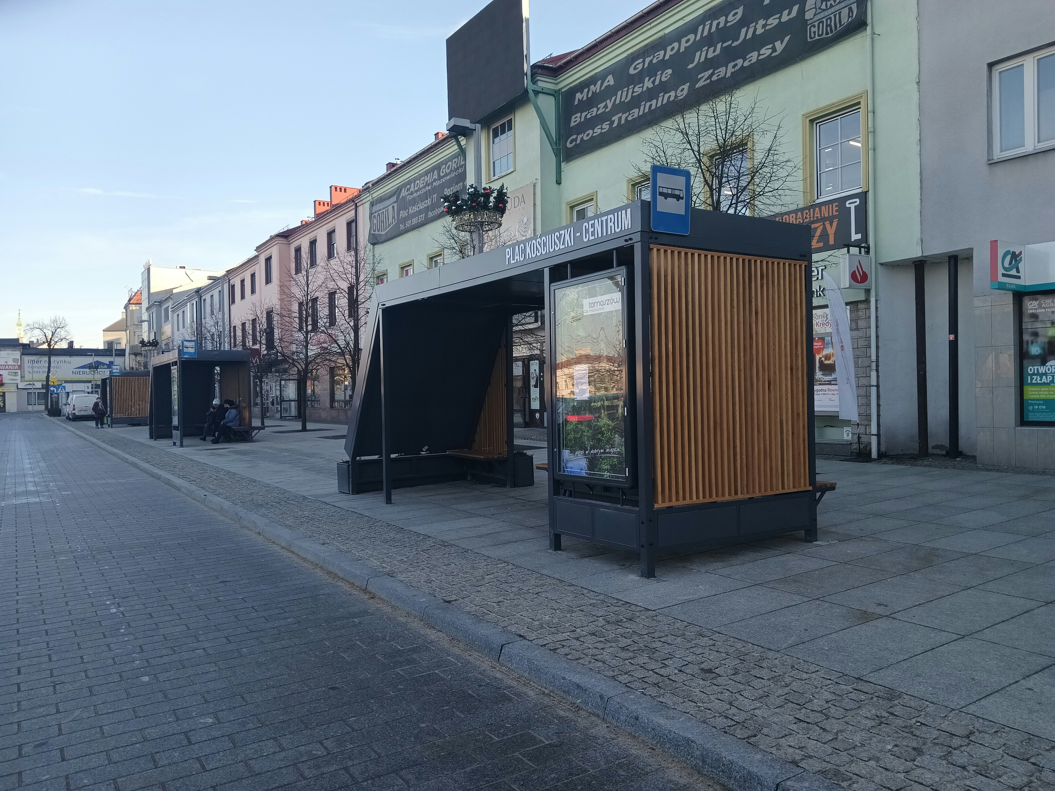 A city street with a bus stop on the side of it photo – Free Car Image ...