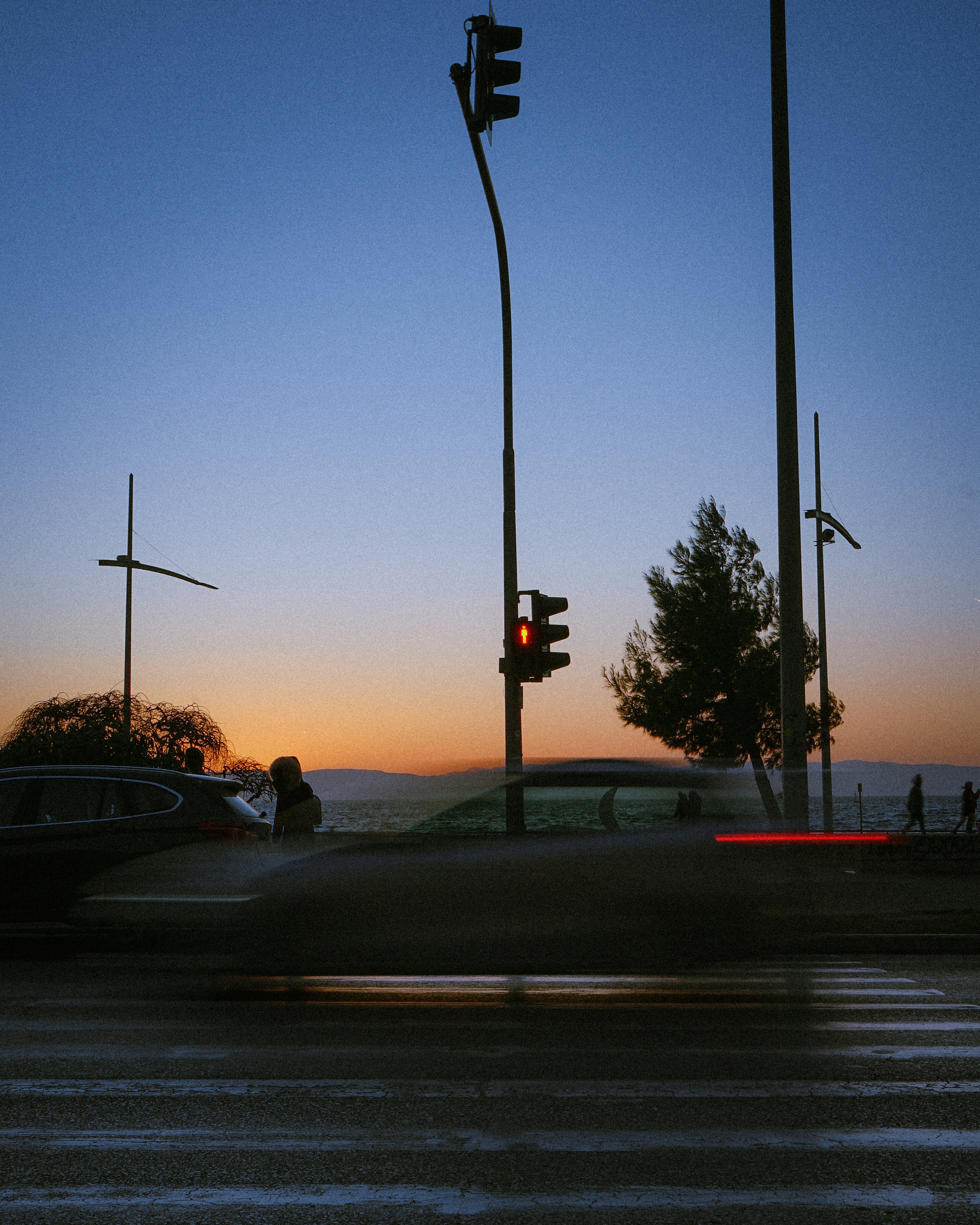 Red Signal at Dusk: Coastal Crosswalk Beneath a Quiet Sea Sunset