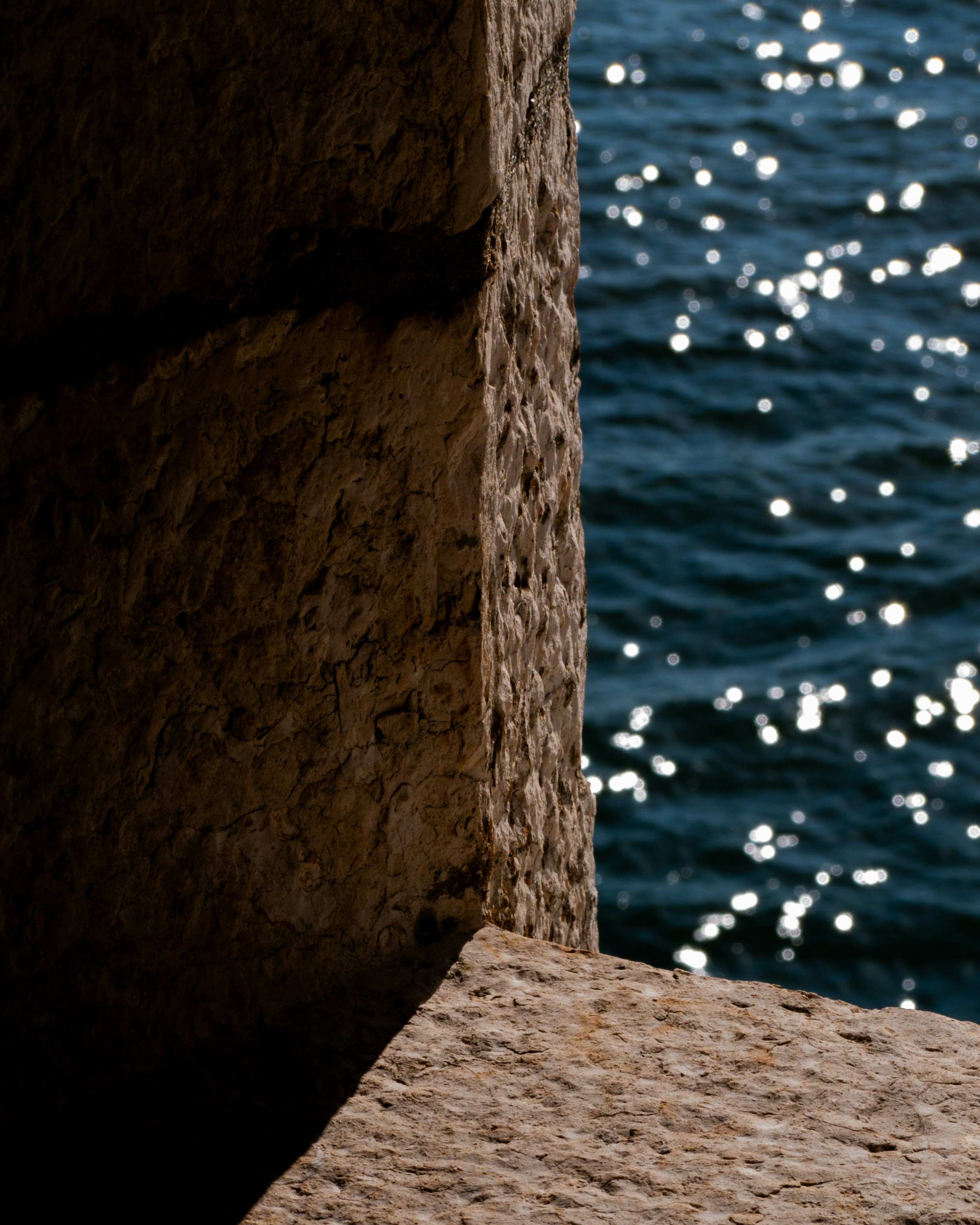 Rugged Seaside Corner: Sunlit Stone Beside Moving Blue